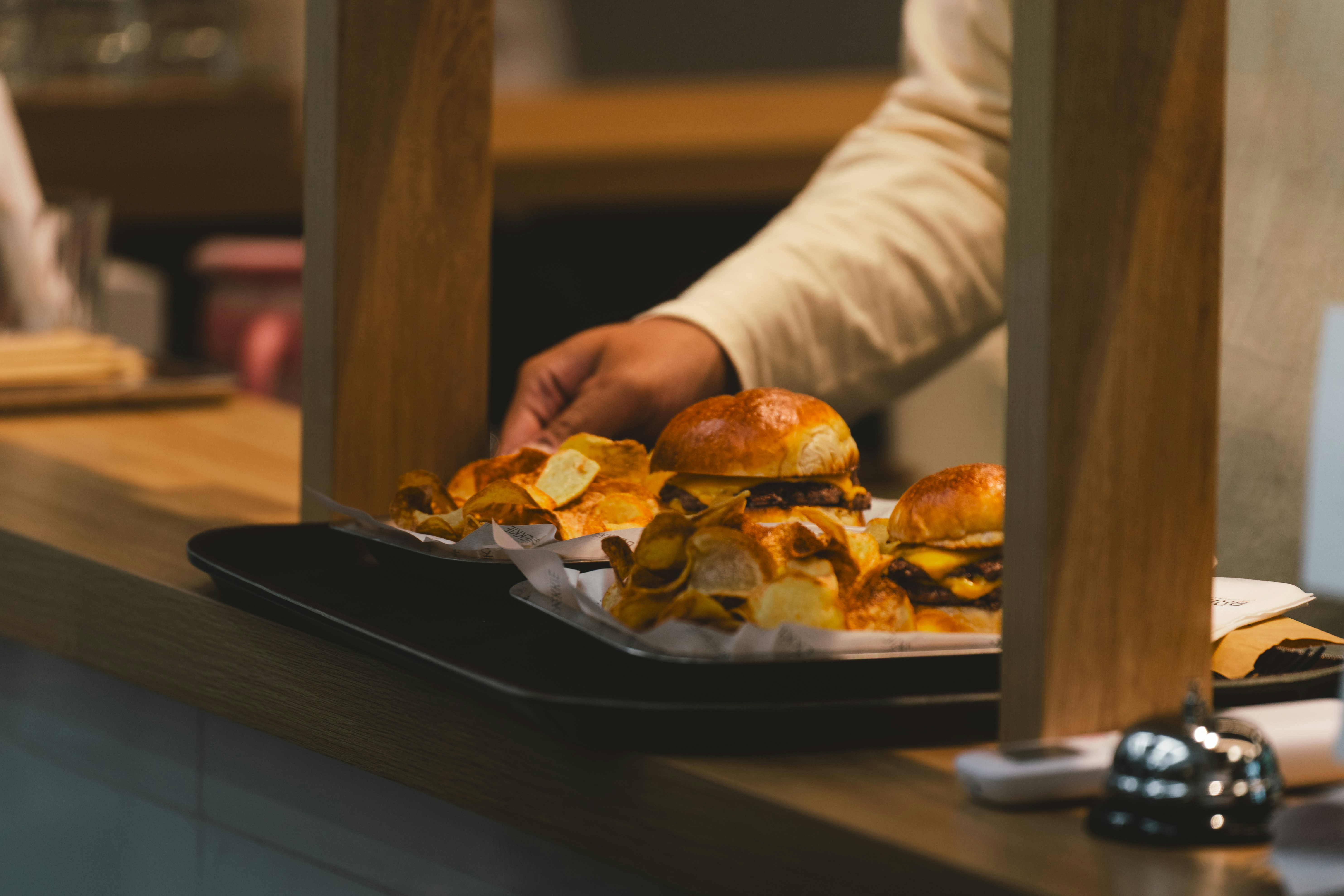 Hands at the Grill: Burgers Rest on a Tray Beneath Wooden Dividers