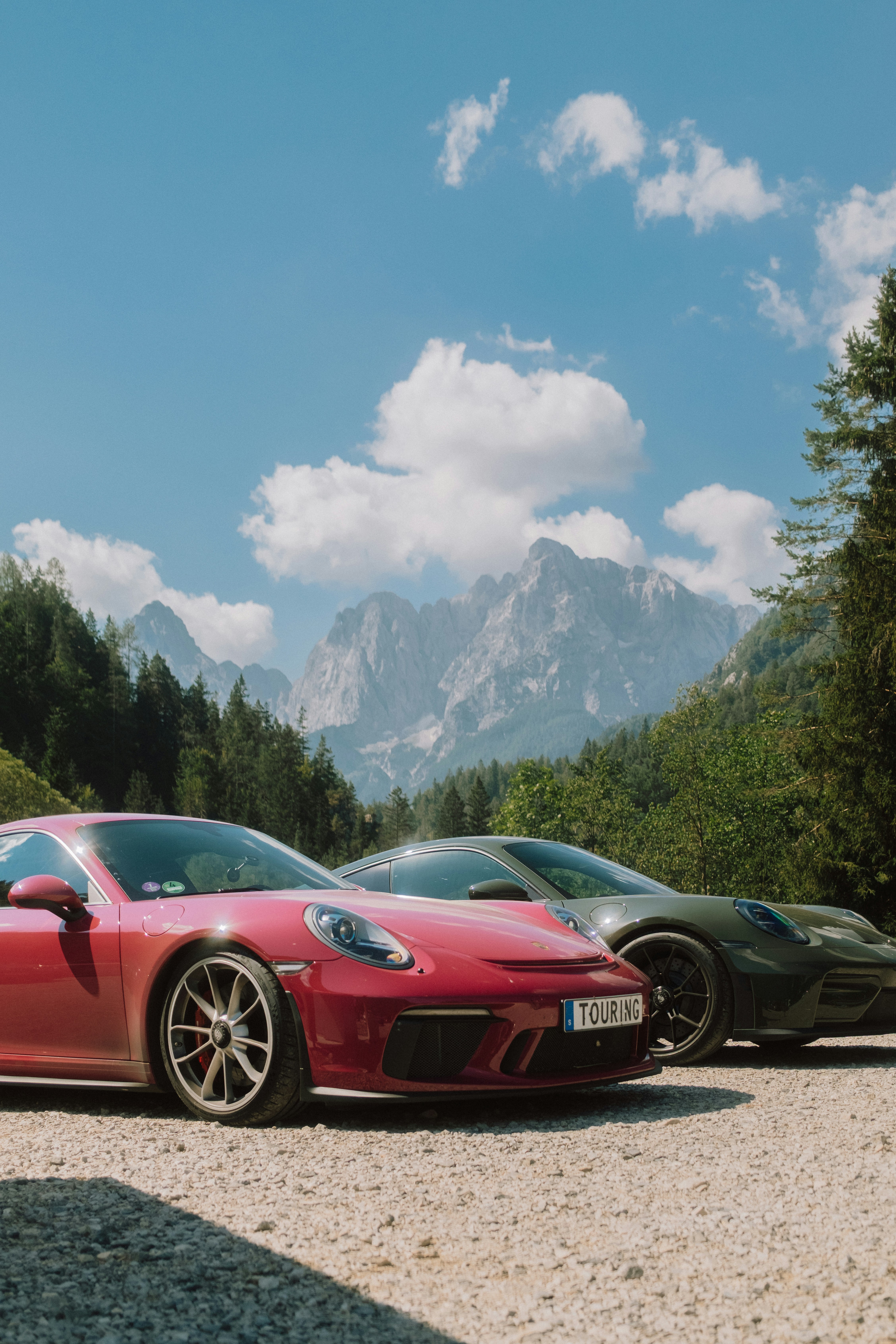 Sunlit Alpine Parking: Red Porsche Front and Center