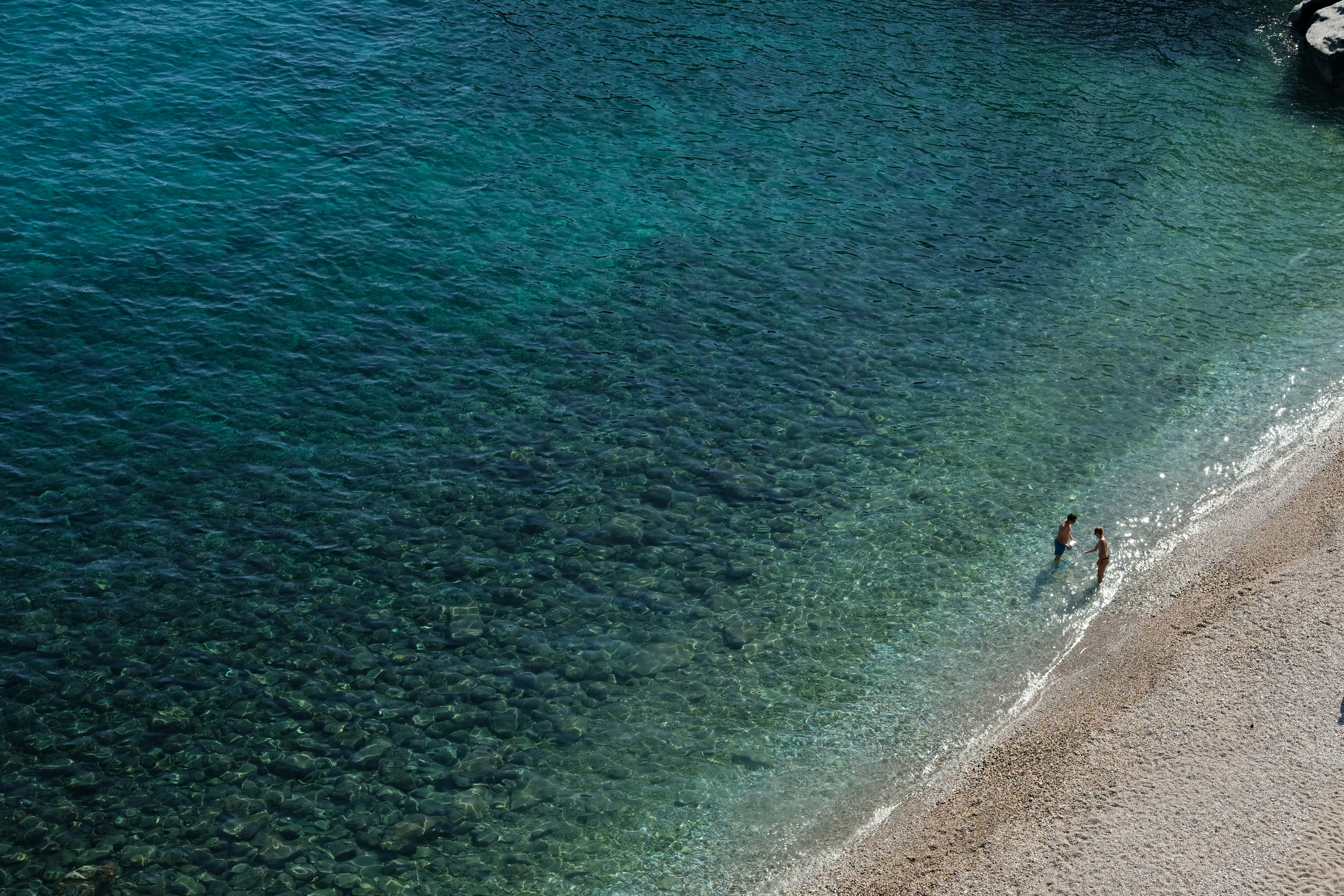 Emerald Shoreline: Two Figures Walk the Quiet Edge of Crystal Waters