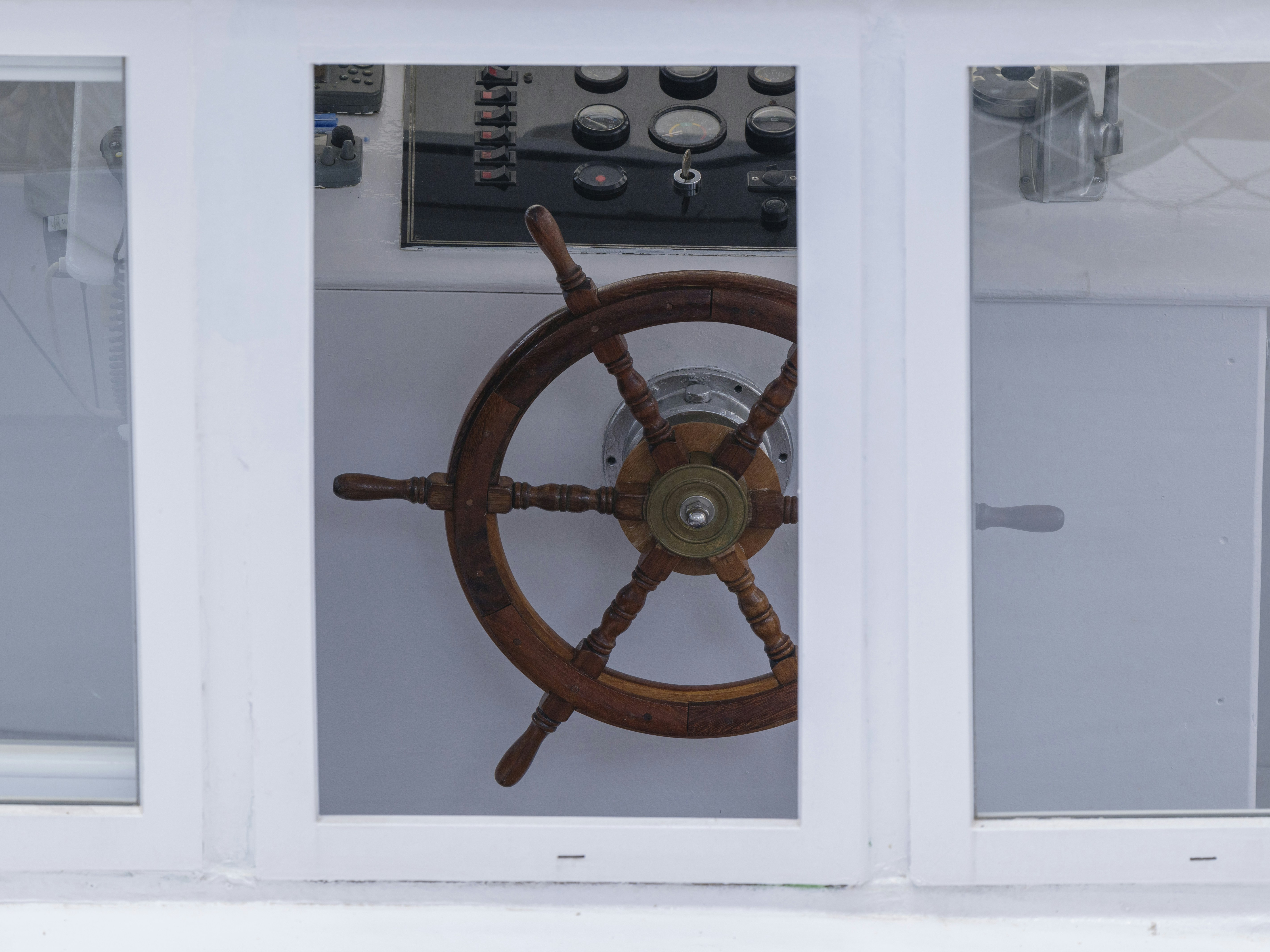 Steering Wheel in Cabin Window: A Ship's Helm Framed by Glass