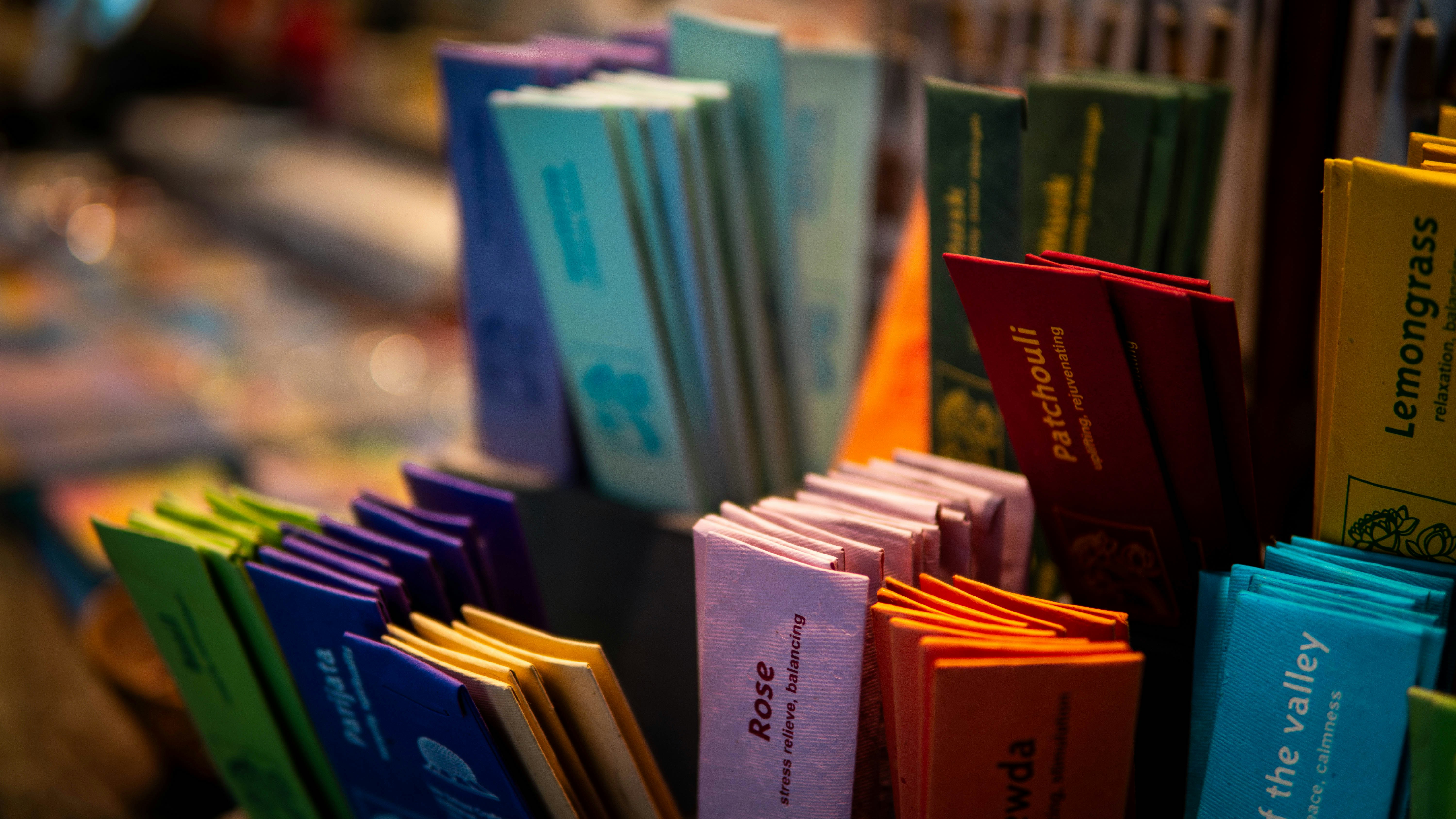 Colorful book spines arranged in a fan-like display, with each panel showing varied hues and text panels; the setup emphasizes the vibrant spectrum and the tactile texture of the pages.