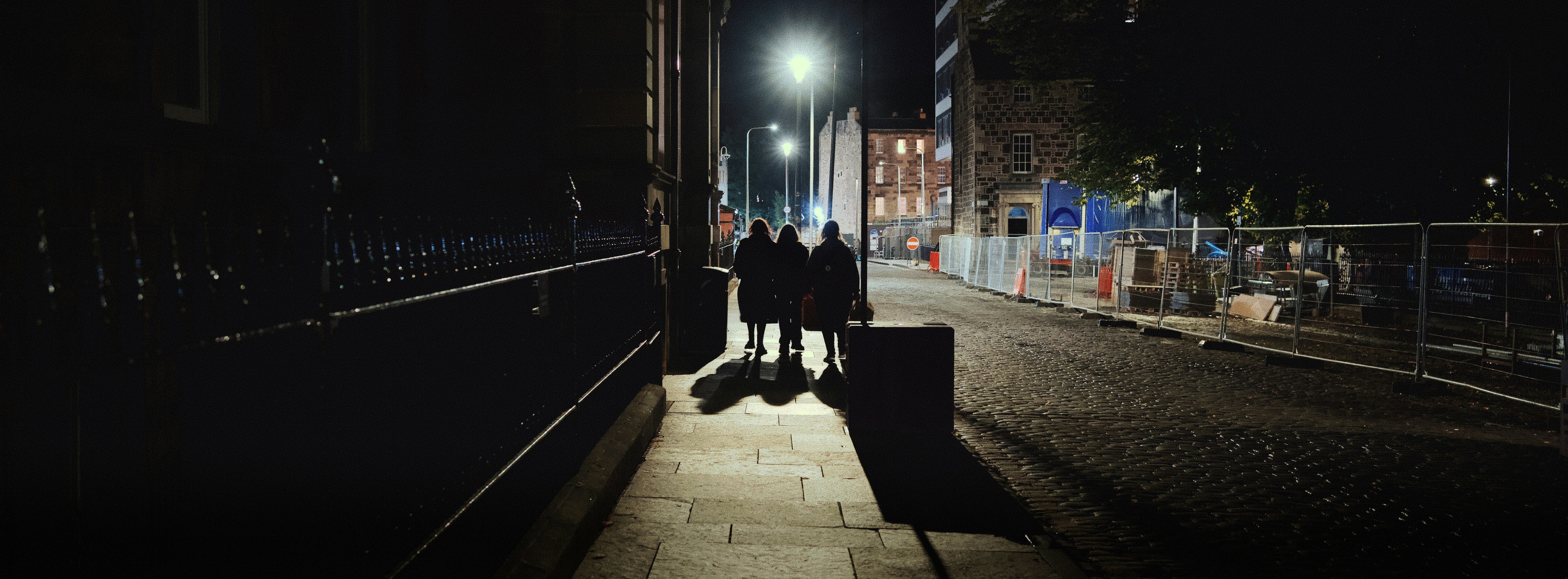 Night Walk: silhouettes and streetlight silhouettes converge on a quiet riverside path