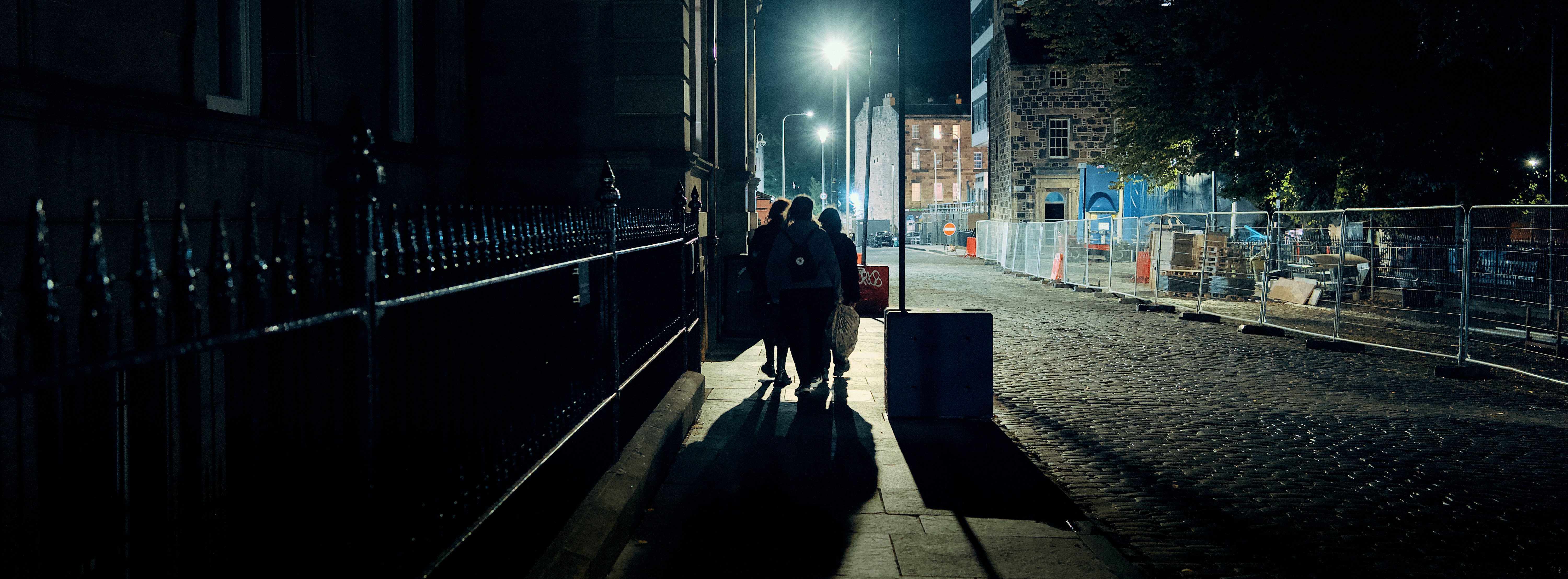 Night Stroll: silhouettes and streetlight glow in a quiet urban corridor