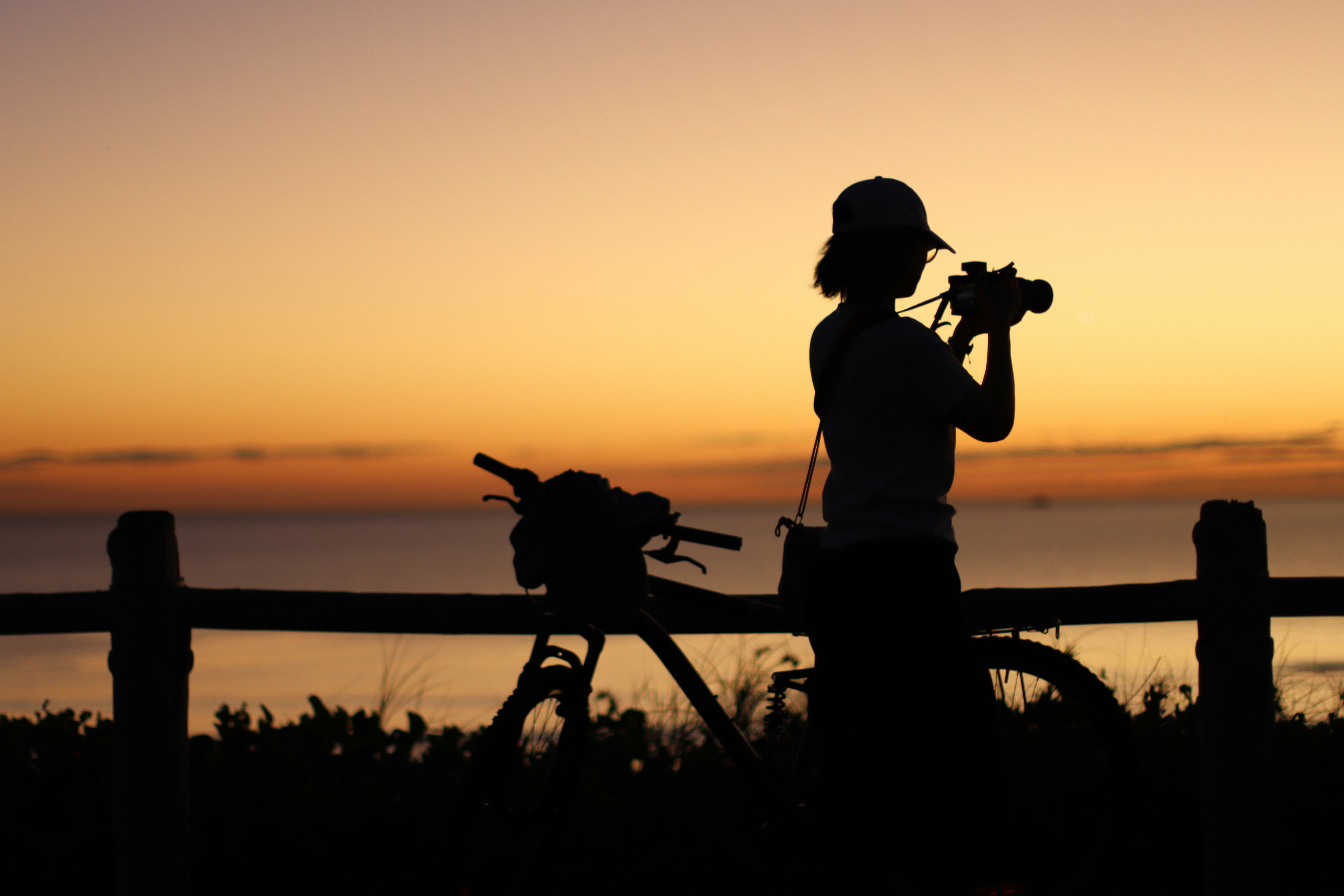 Silhouette at Dusk: A Photographer's Quiet Moment by the Fence