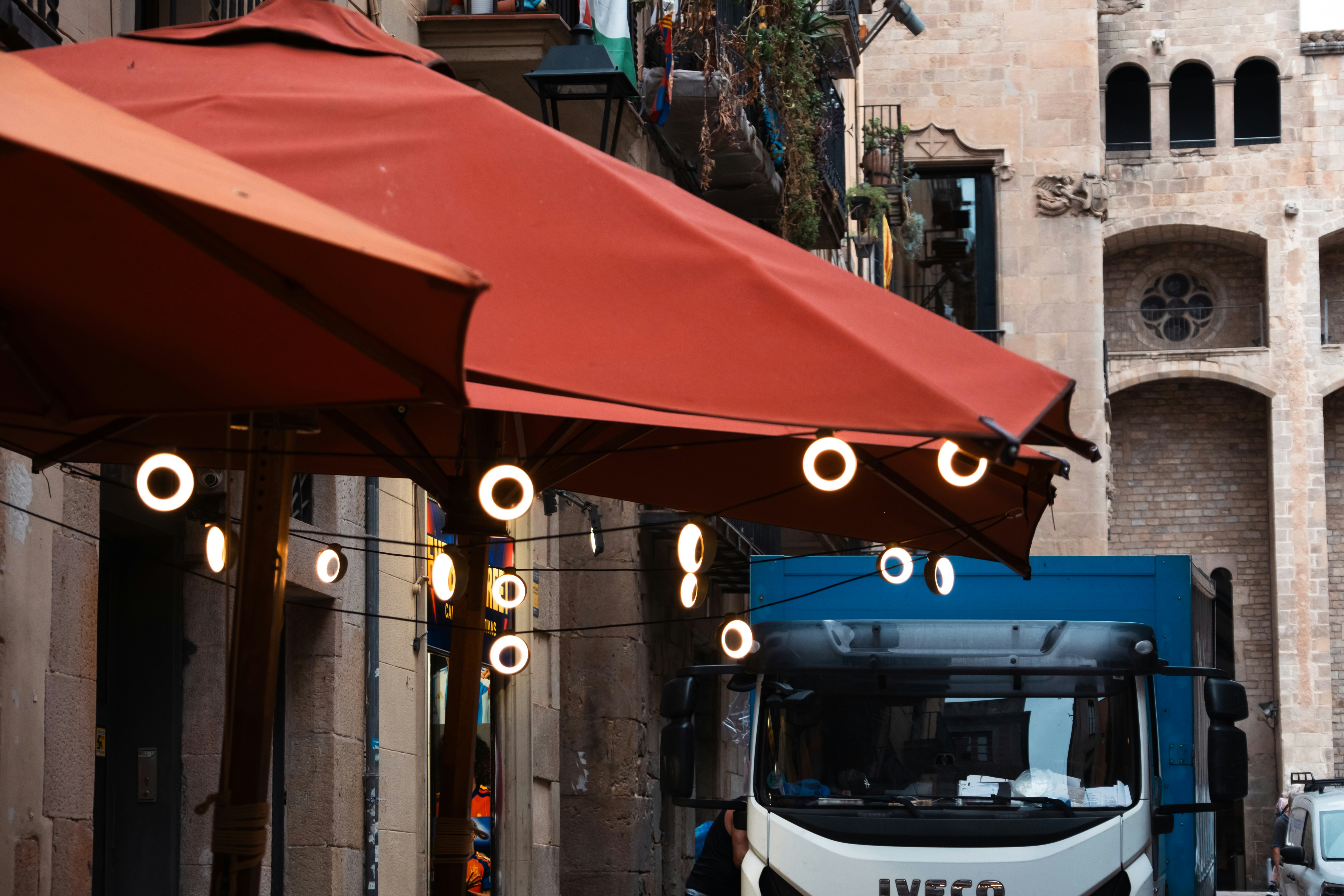 Red Canopy, Quiet Street: Lanterns and A Truck in a Medieval Alley