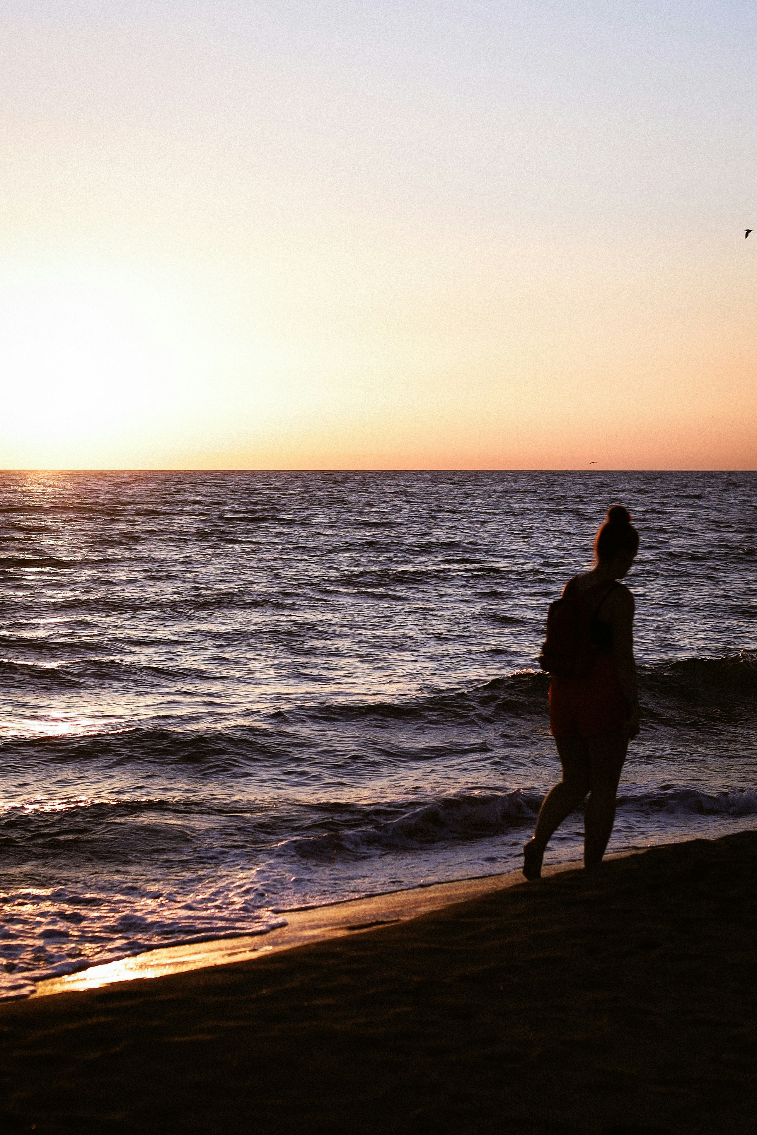 Sunset Silhouette: A lone wanderer by the shoreline