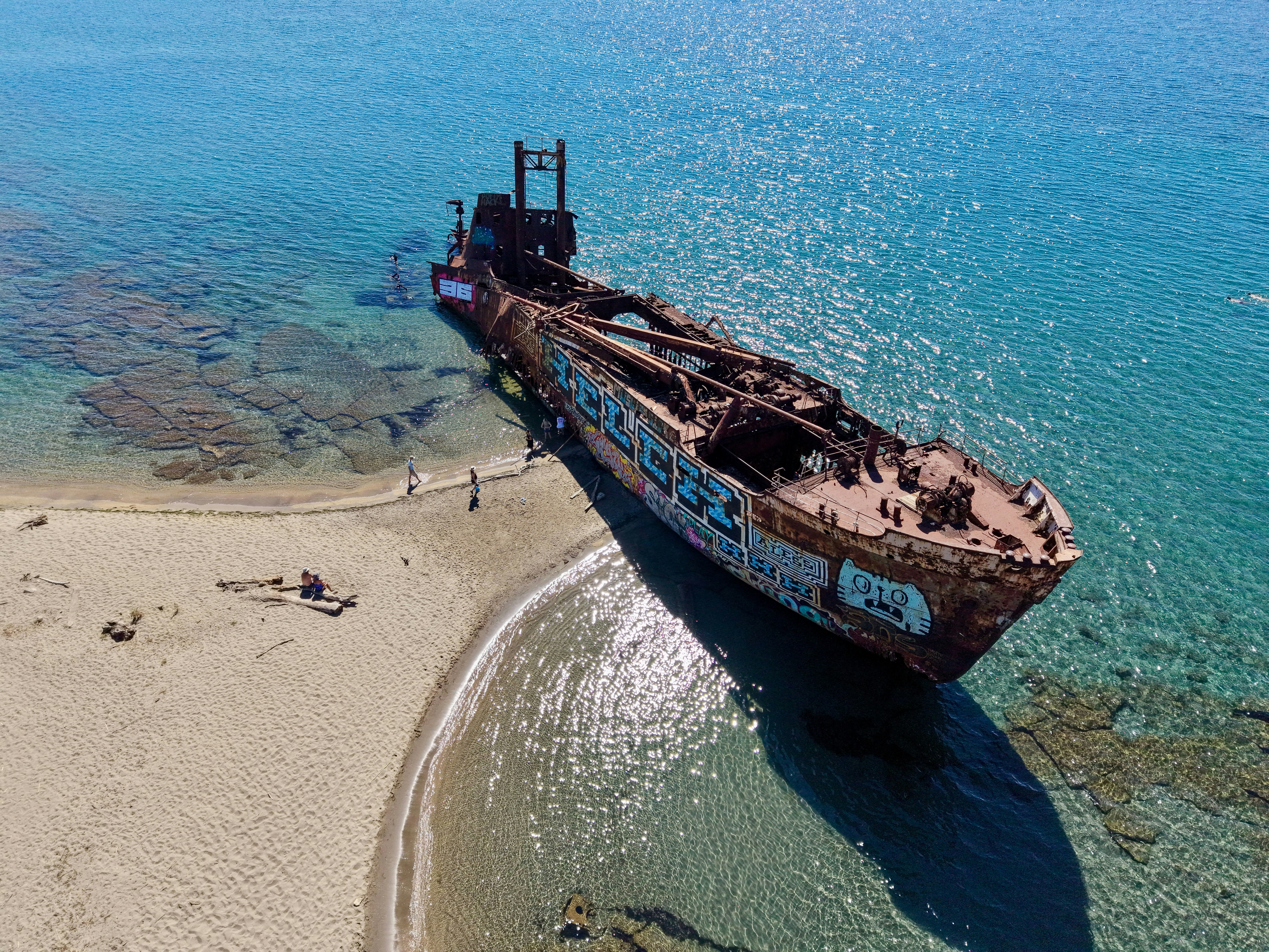Sunken Vessel, Clear Waters: Aerial Portrait of a Rusting Shipresting on a Shallow Beach
