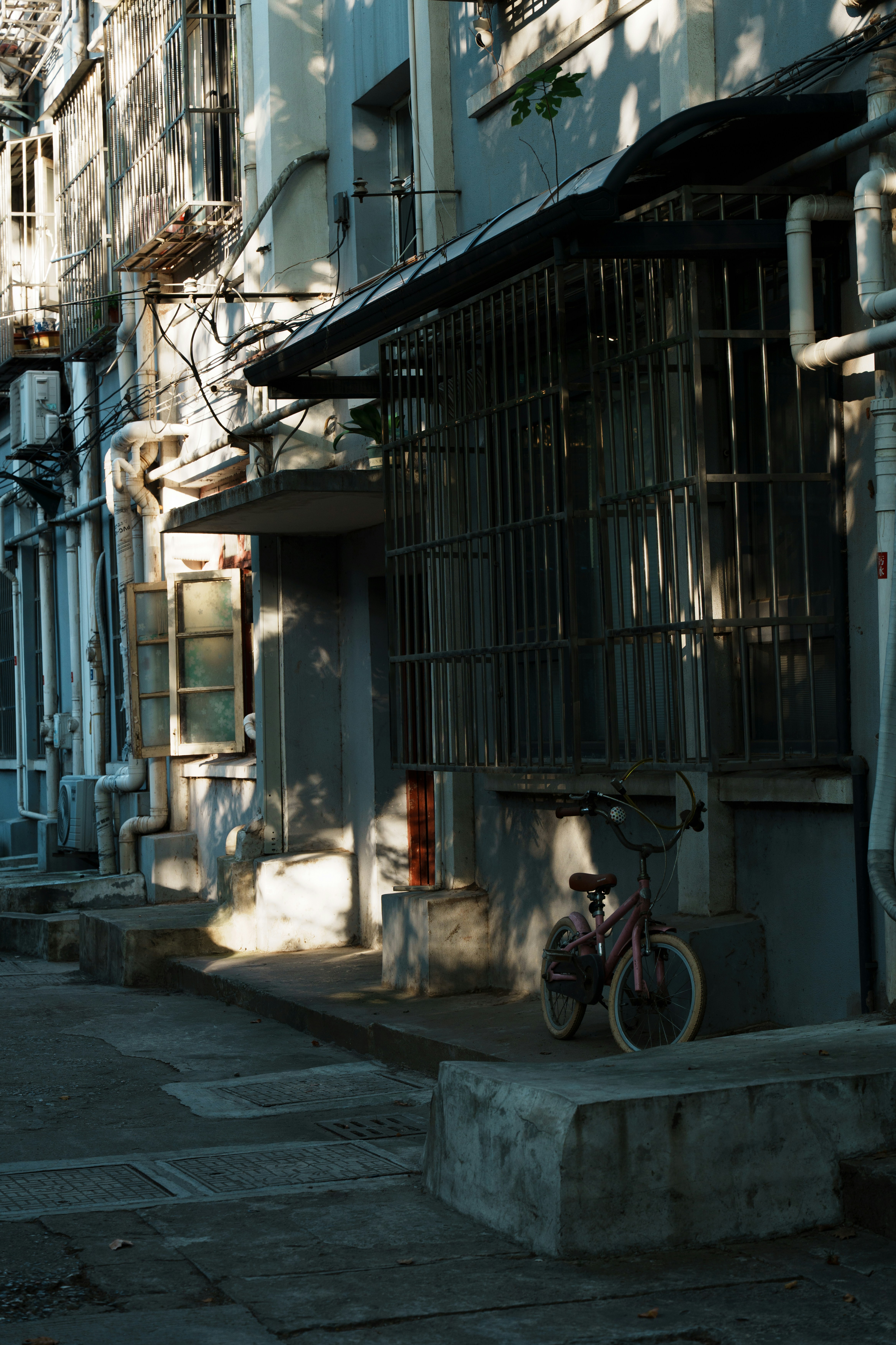 Narrow Alleyway with Sunlit Courtyard and Vintage Bicycle