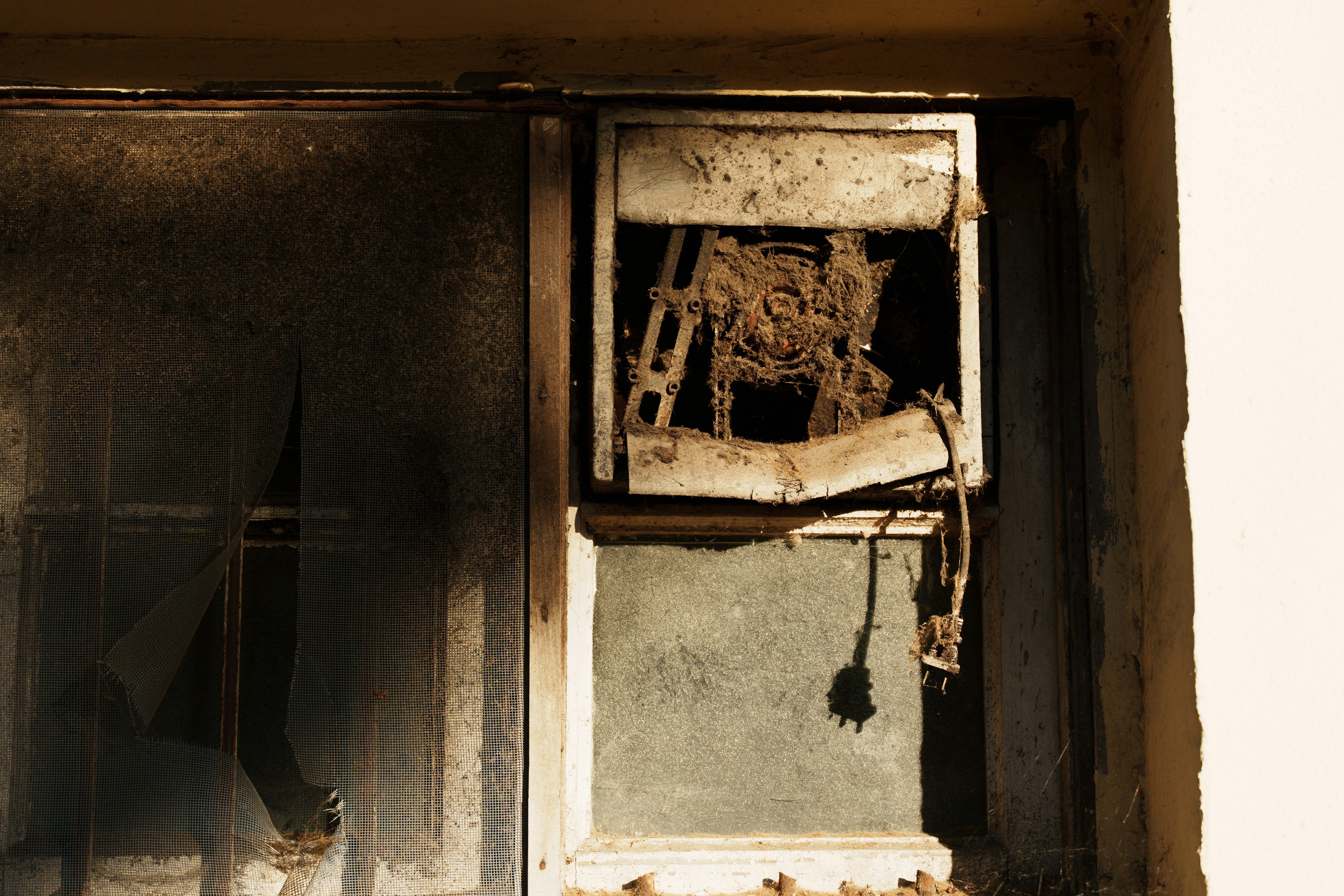 Dusty Vent Window: A Silent, Sun-bleached Detail in an Abandoned Corner