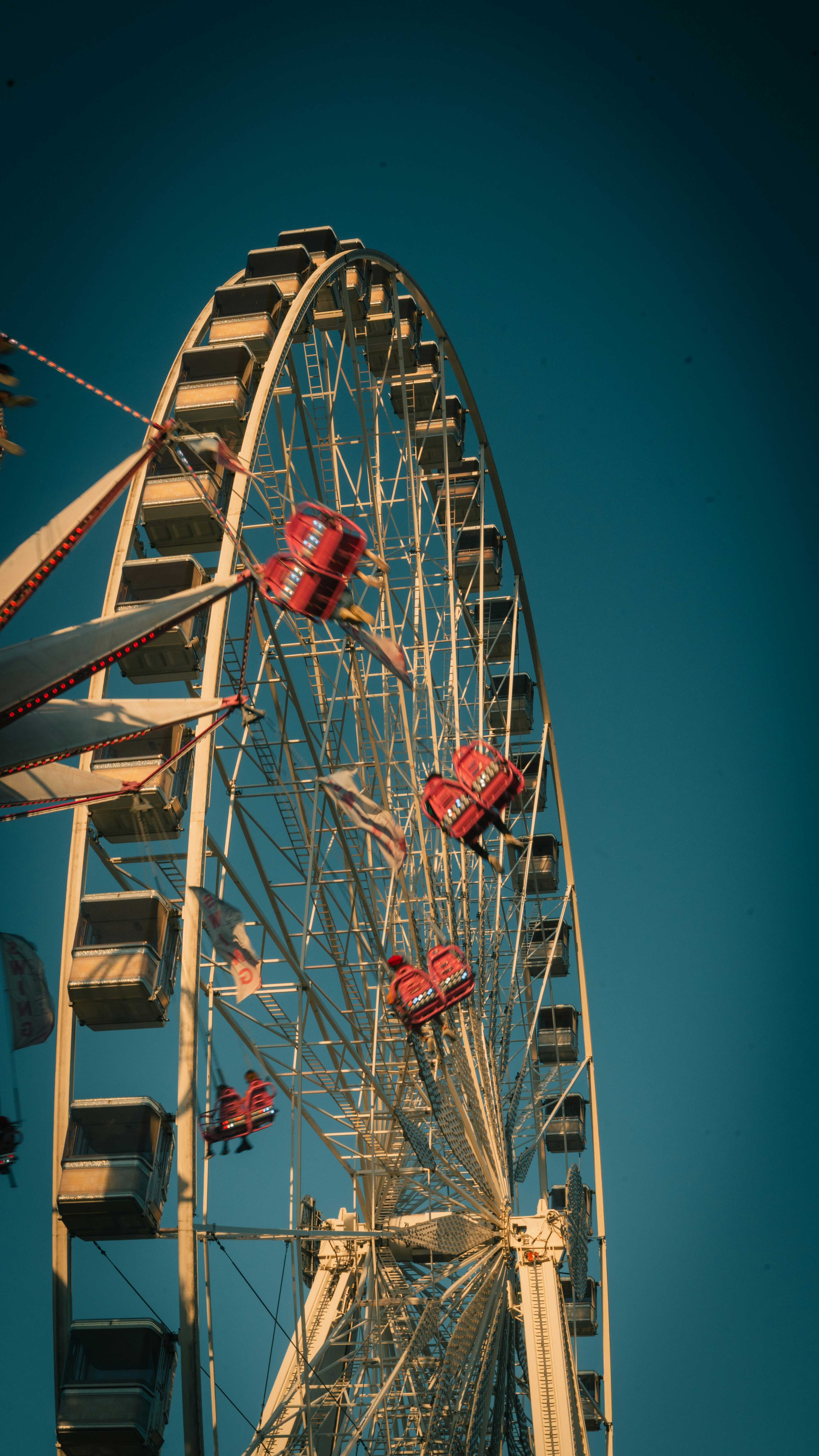 A large white ferris wheel with red passenger cars against a clear blue sky