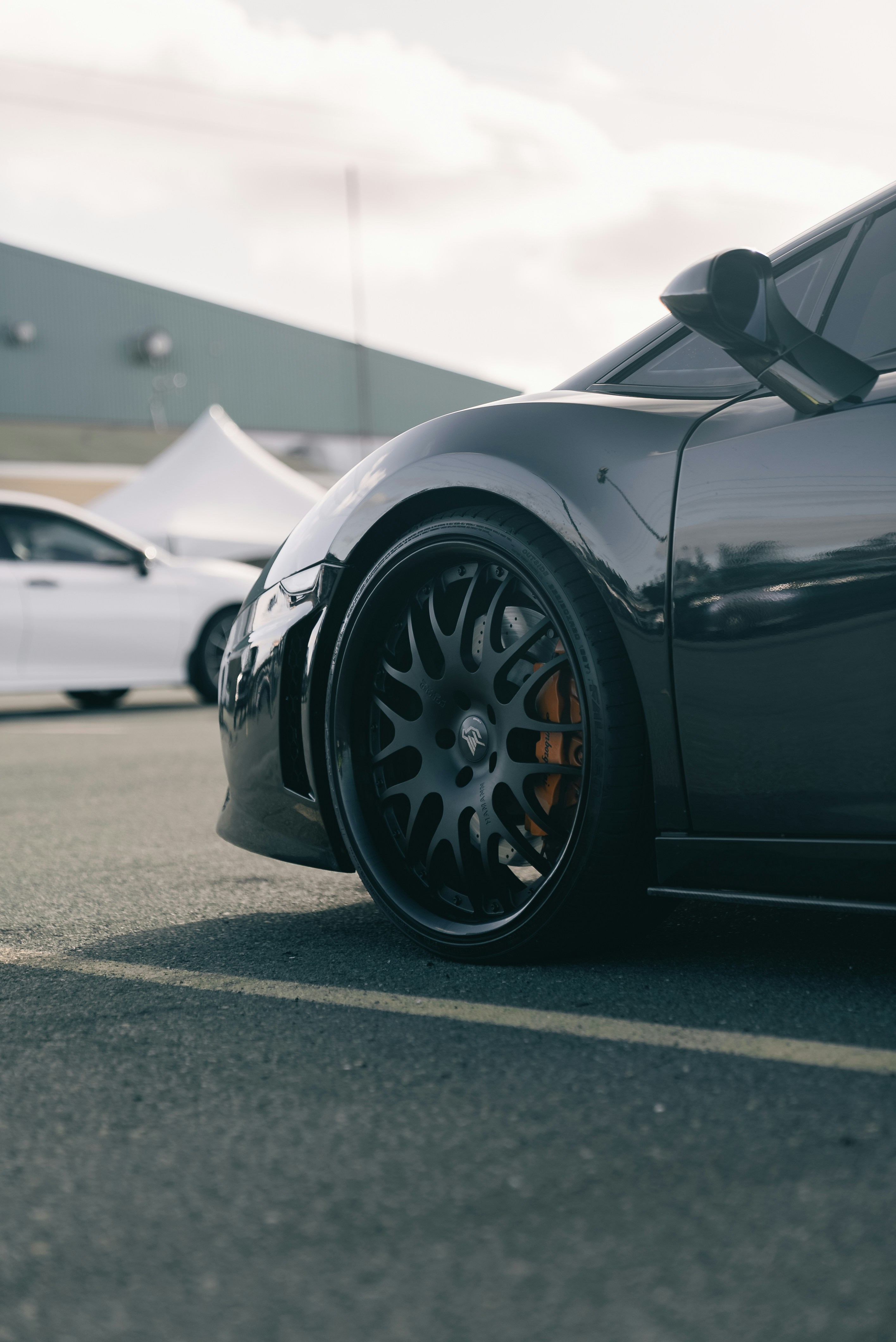 Low-Angle Close-Up of a Glossy Black Porsche Wheel at Car Meet