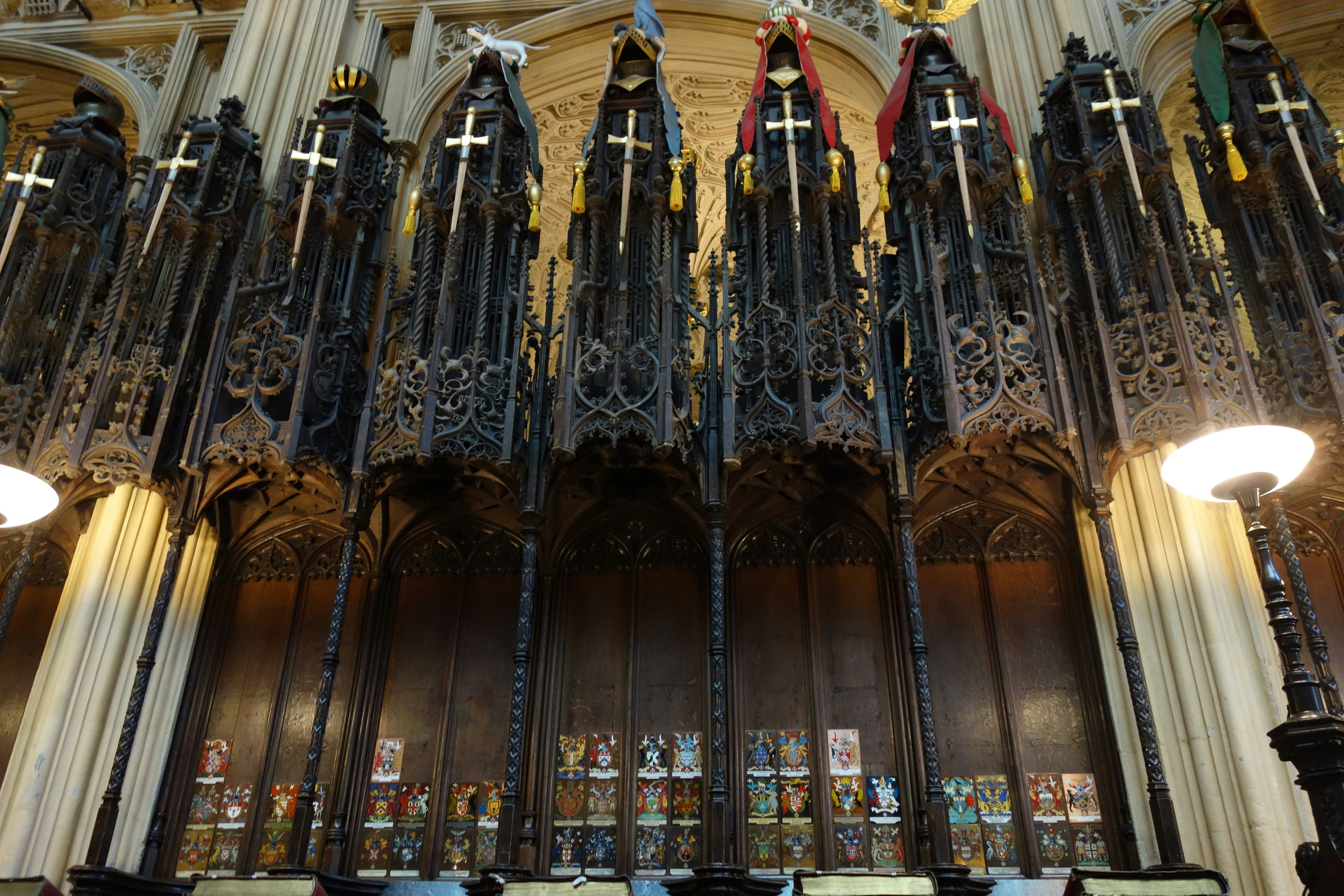 Intricate ironwork railing and stained glass panels line a cathedral-like interior, with warm lighting casting highlights on the ornate details.