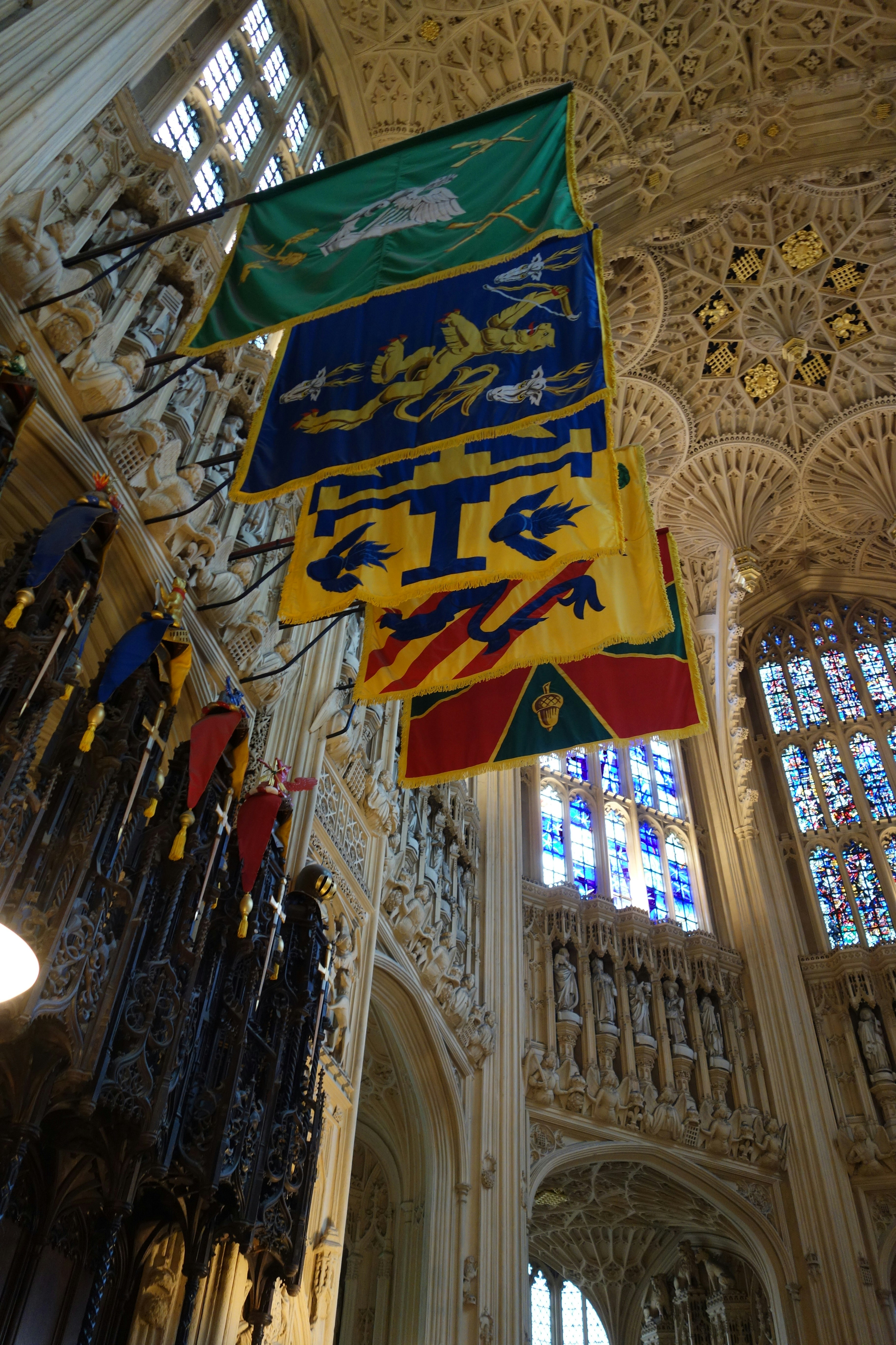 Suspended banners in a vaulted hall: a cascade of color over intricate stonework