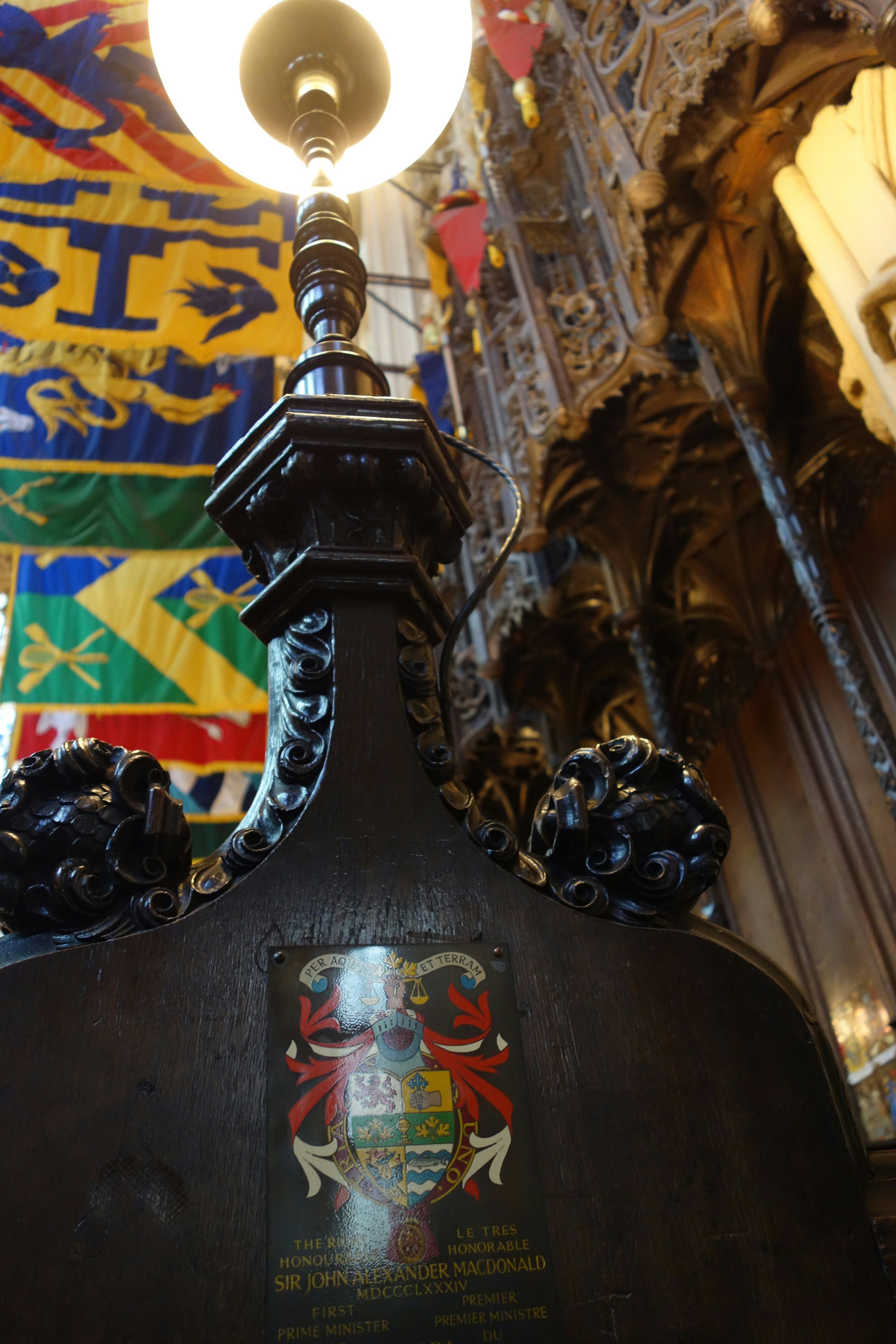 Ornate Lamp Post Framed by Suspended Heraldry and Gothic Architecture