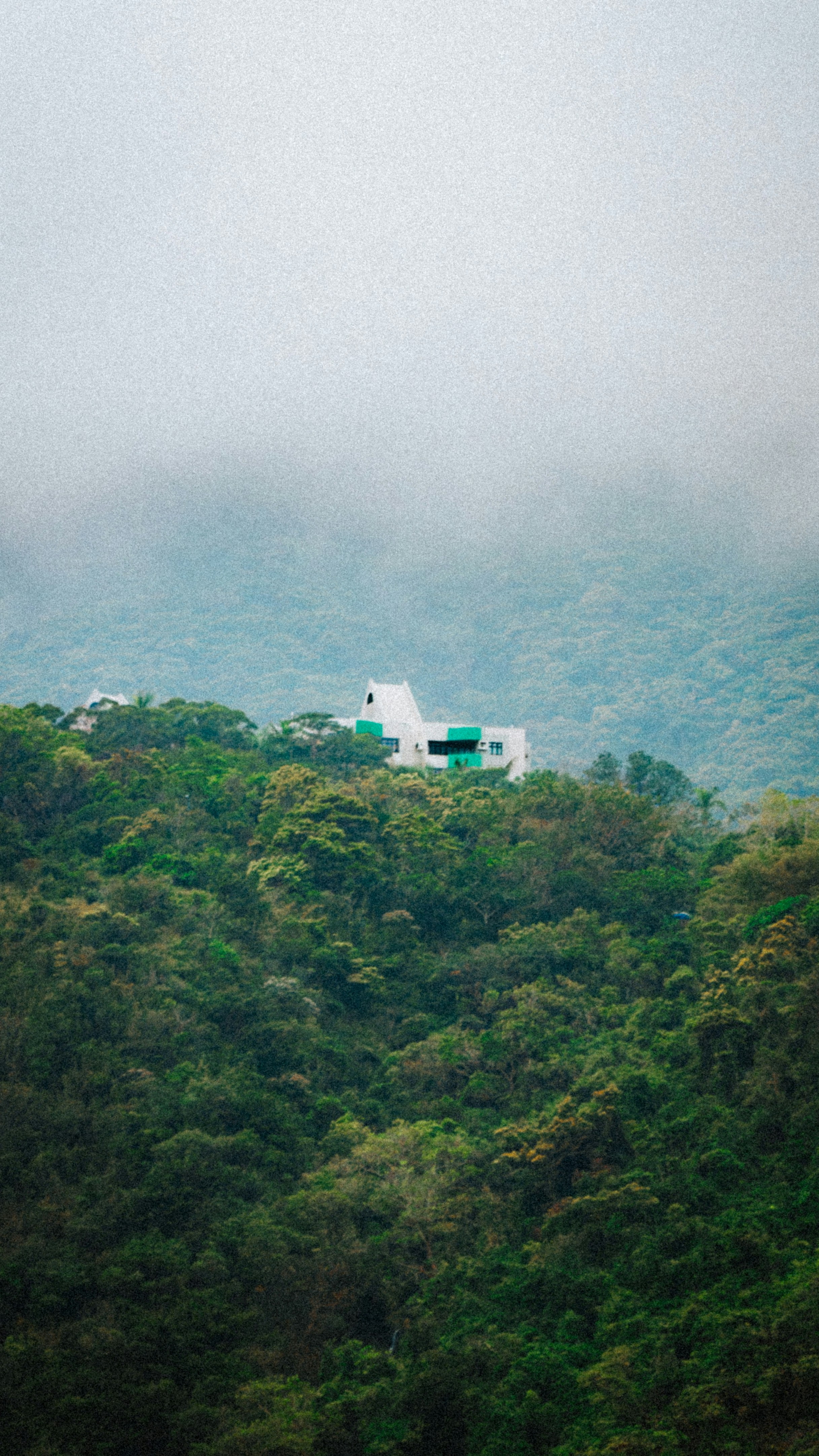A Towering Retreat: White Structure Peeks Over the Verdant Hills