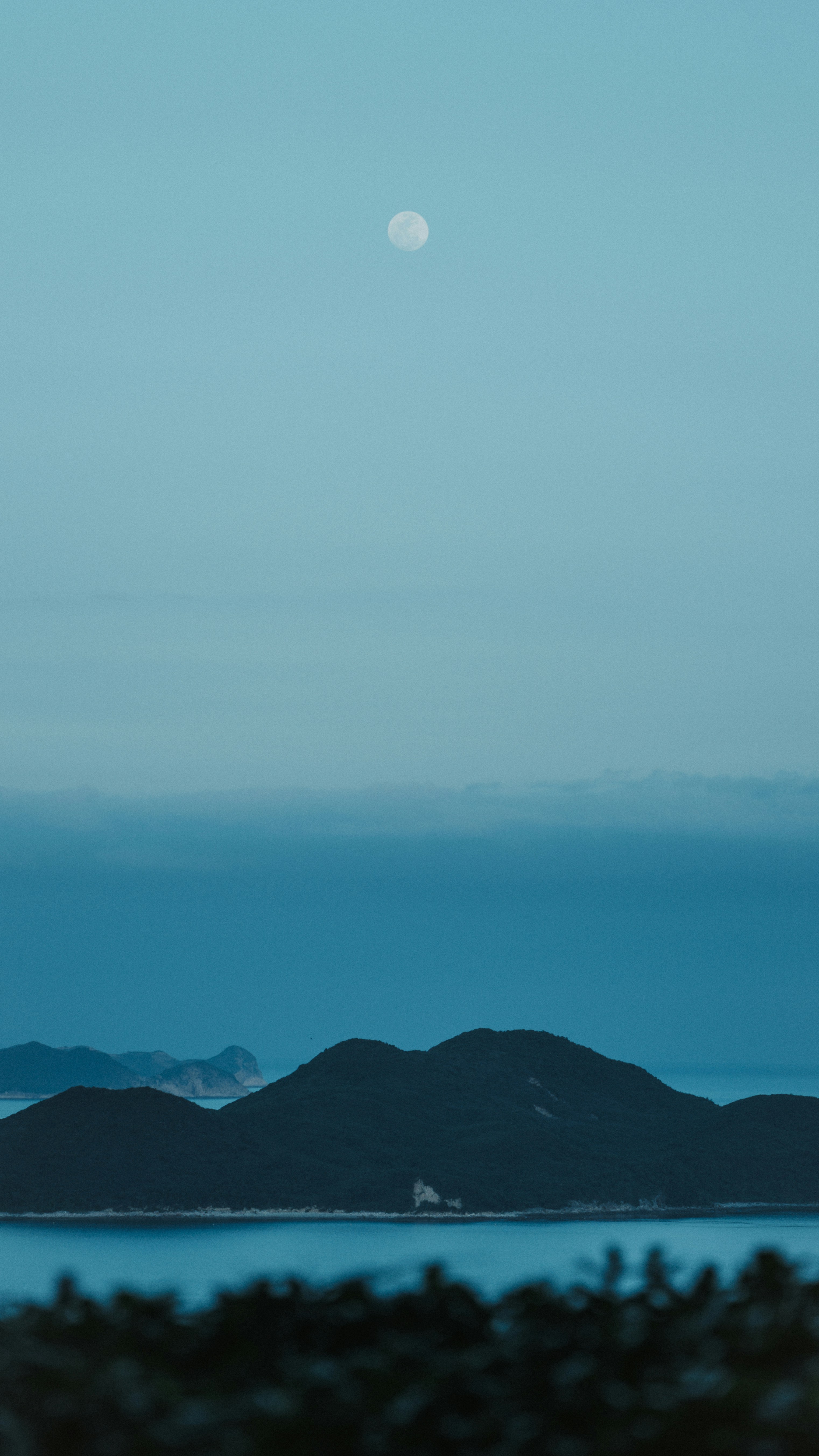 Moon over a tranquil cobalt coastline