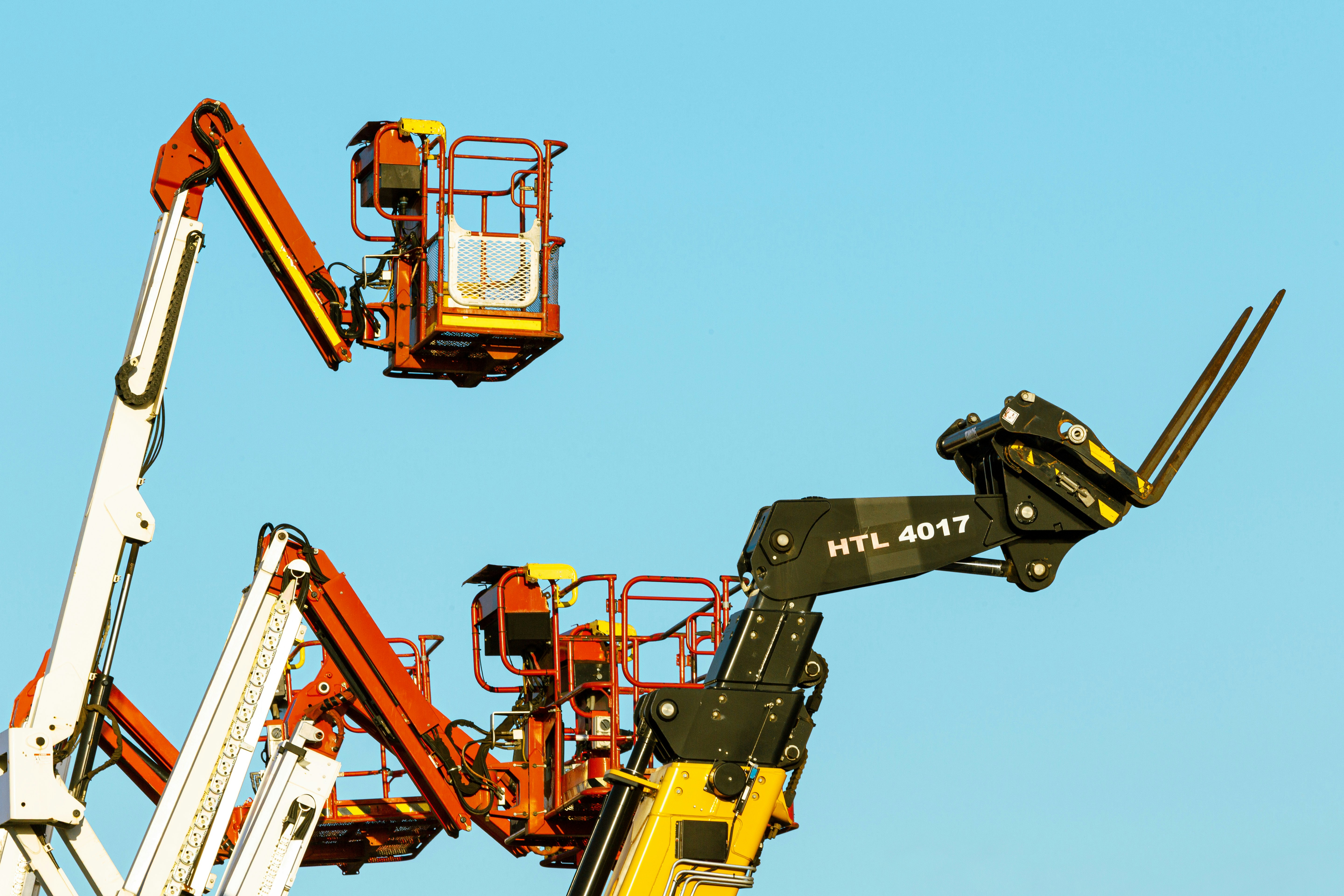 Cranes in Flight: A Sharp Moment of Elevated Machinery Against a Sky-Blue Canvas