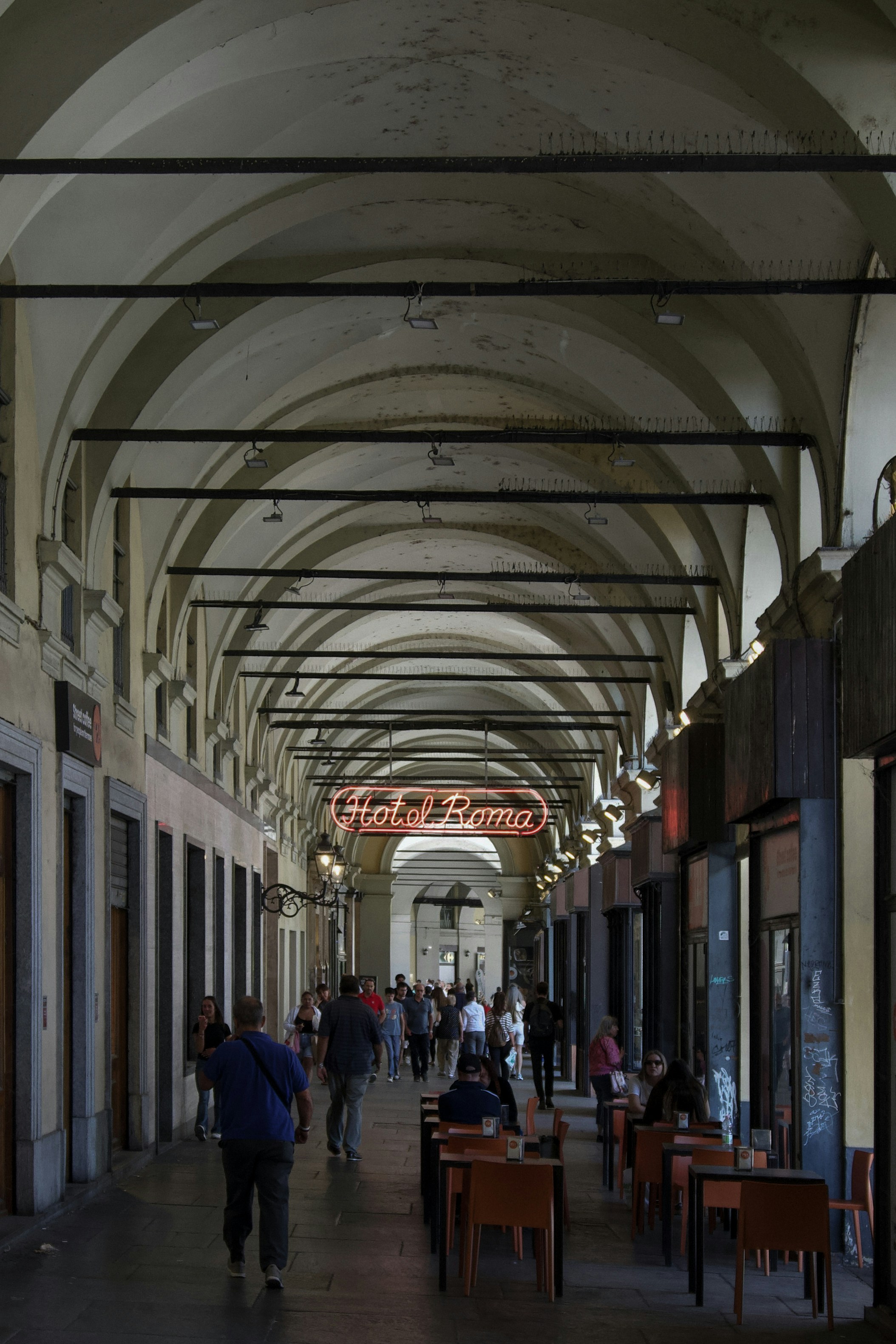 Neon Sign Over a Bustling Colonnade Café Corridor in Rome