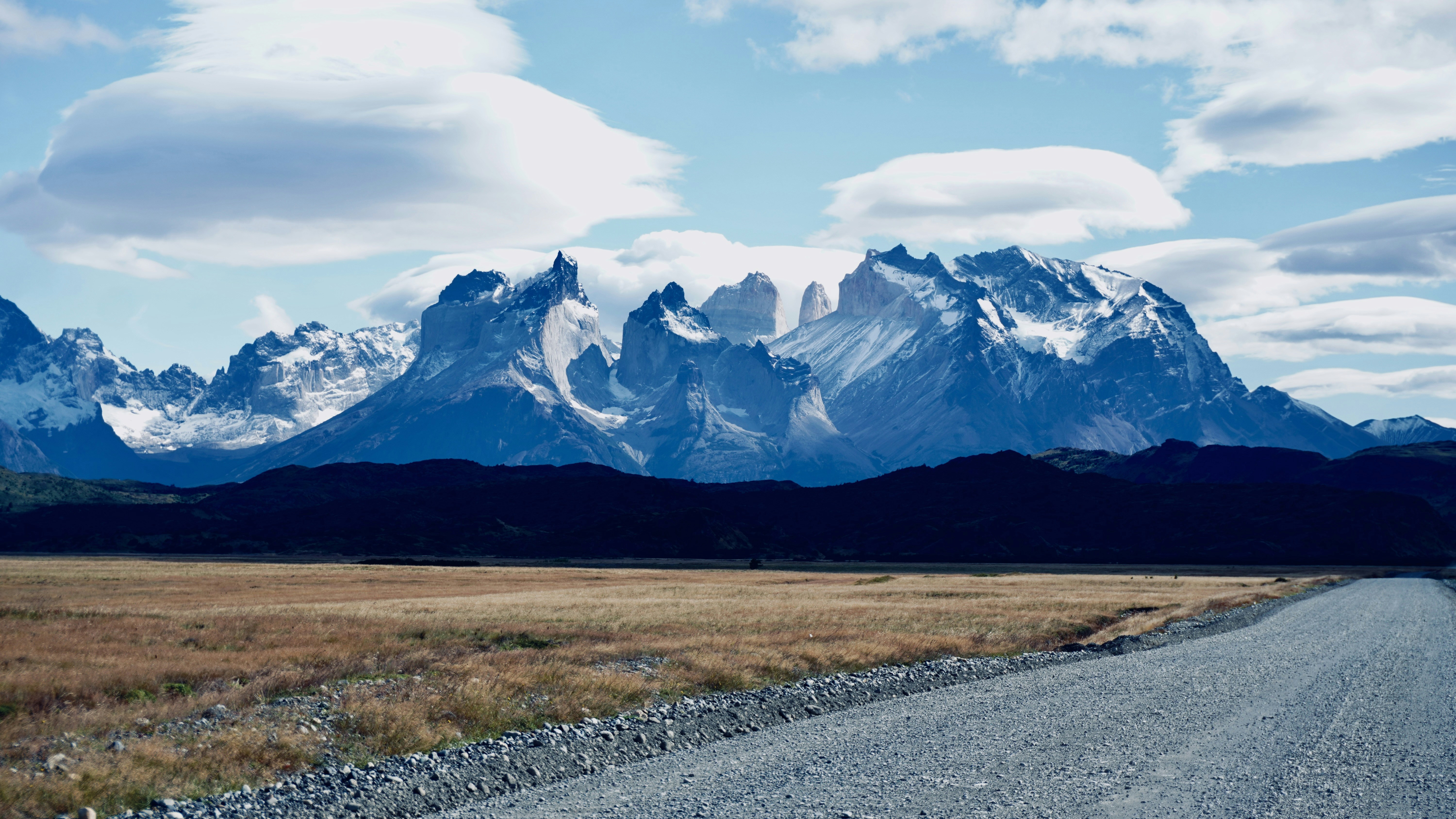Snowy Peaks at Dusk: Mountain Range over a Prairie Road