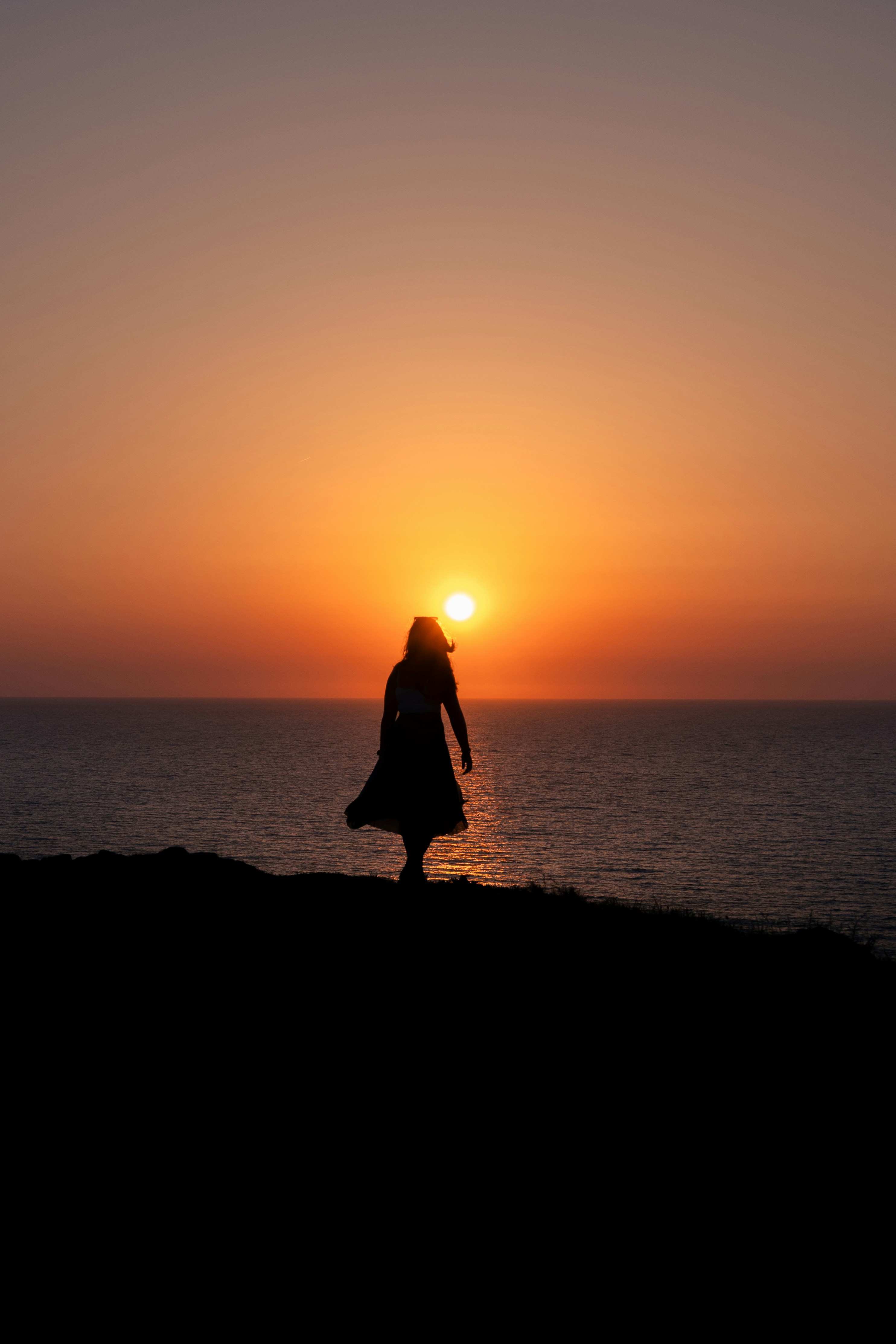 Silhouette at Sundown: A Woman Dancing on the Edge of Light