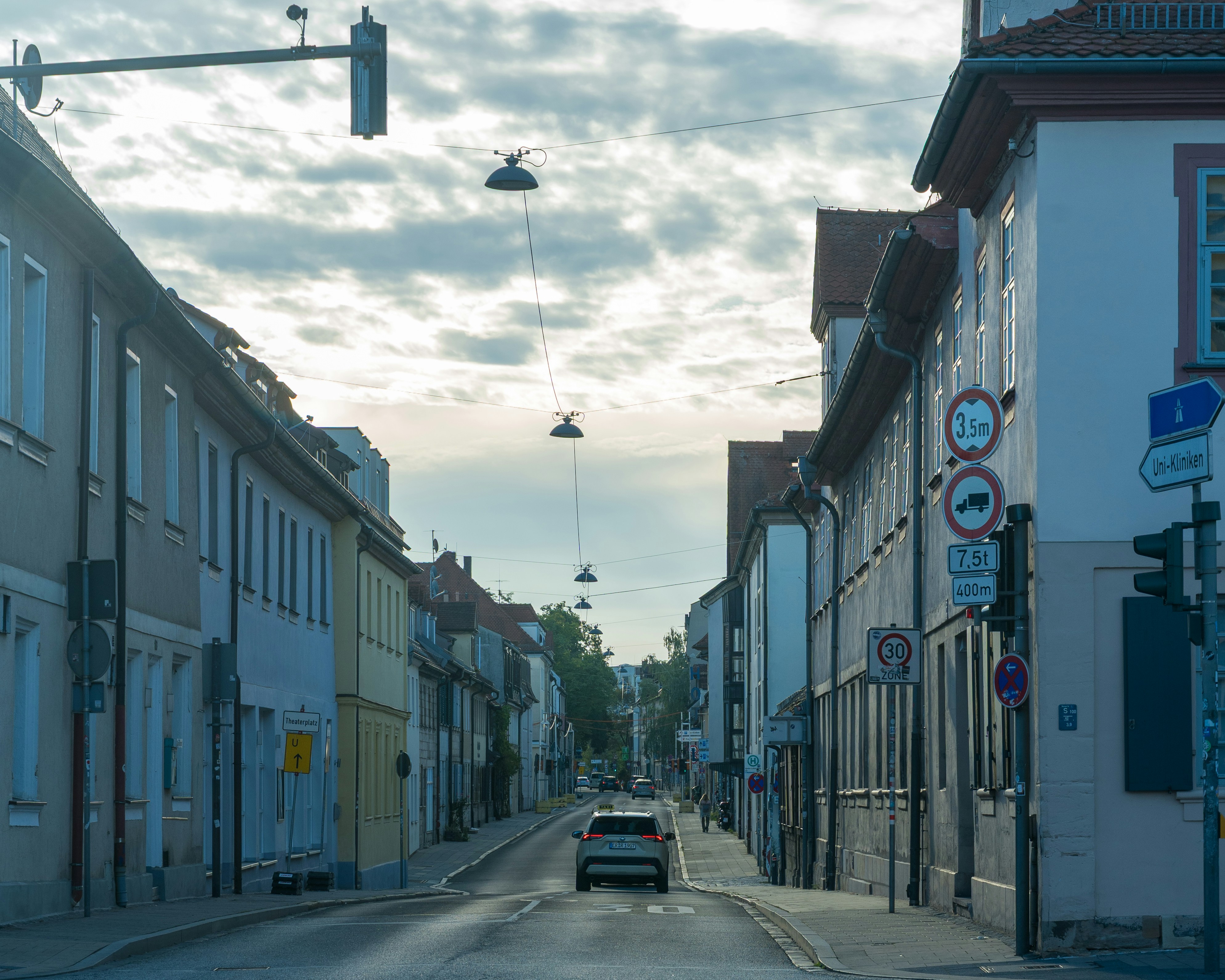 A Quiet Corridor: Cars Retreat Under Evening Street Lamps