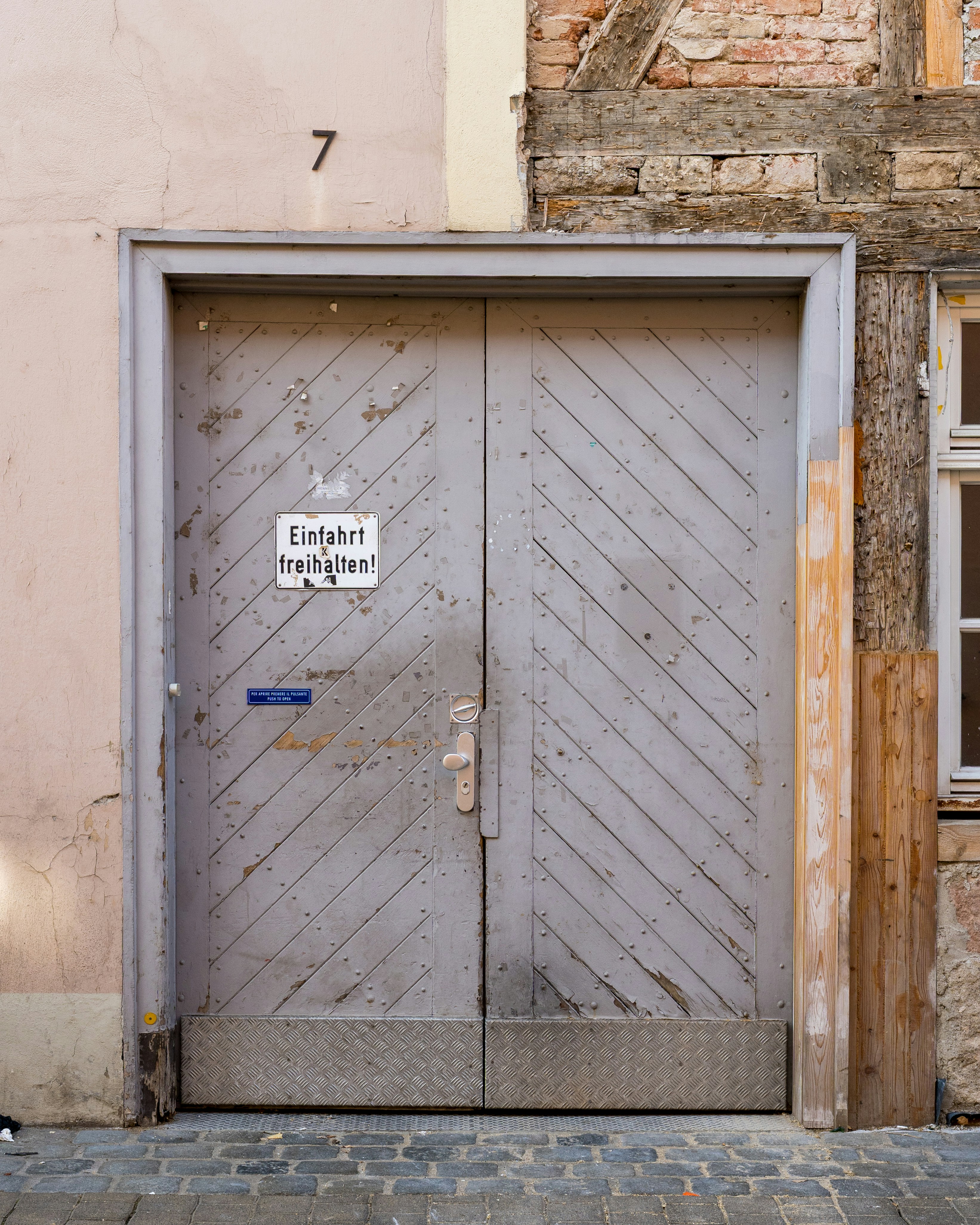 Weathered steel door beneath a weathered timber facade