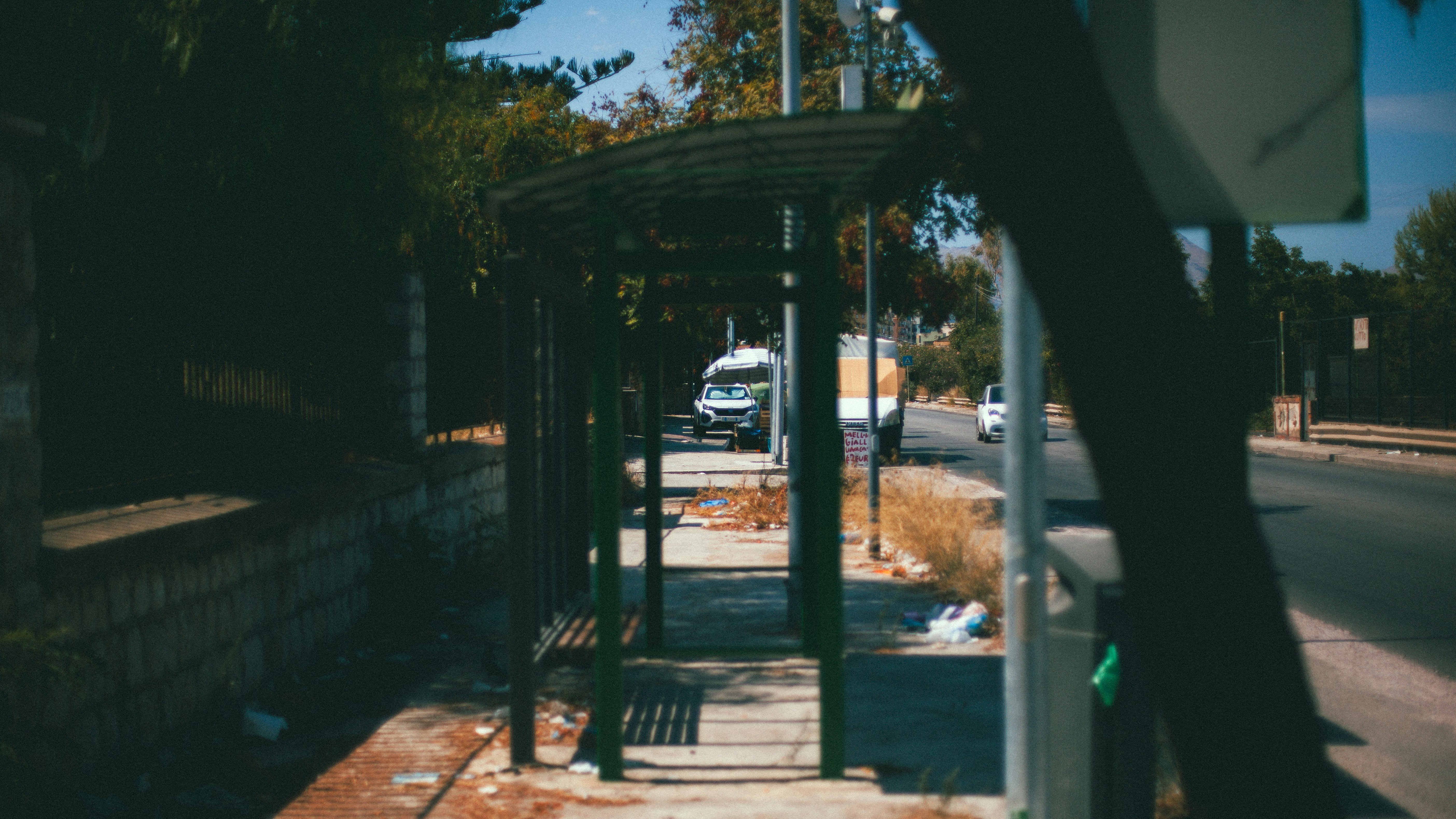 Bus Shelter Corridor: A Quiet Street Scene Framed by Dappled Shadows