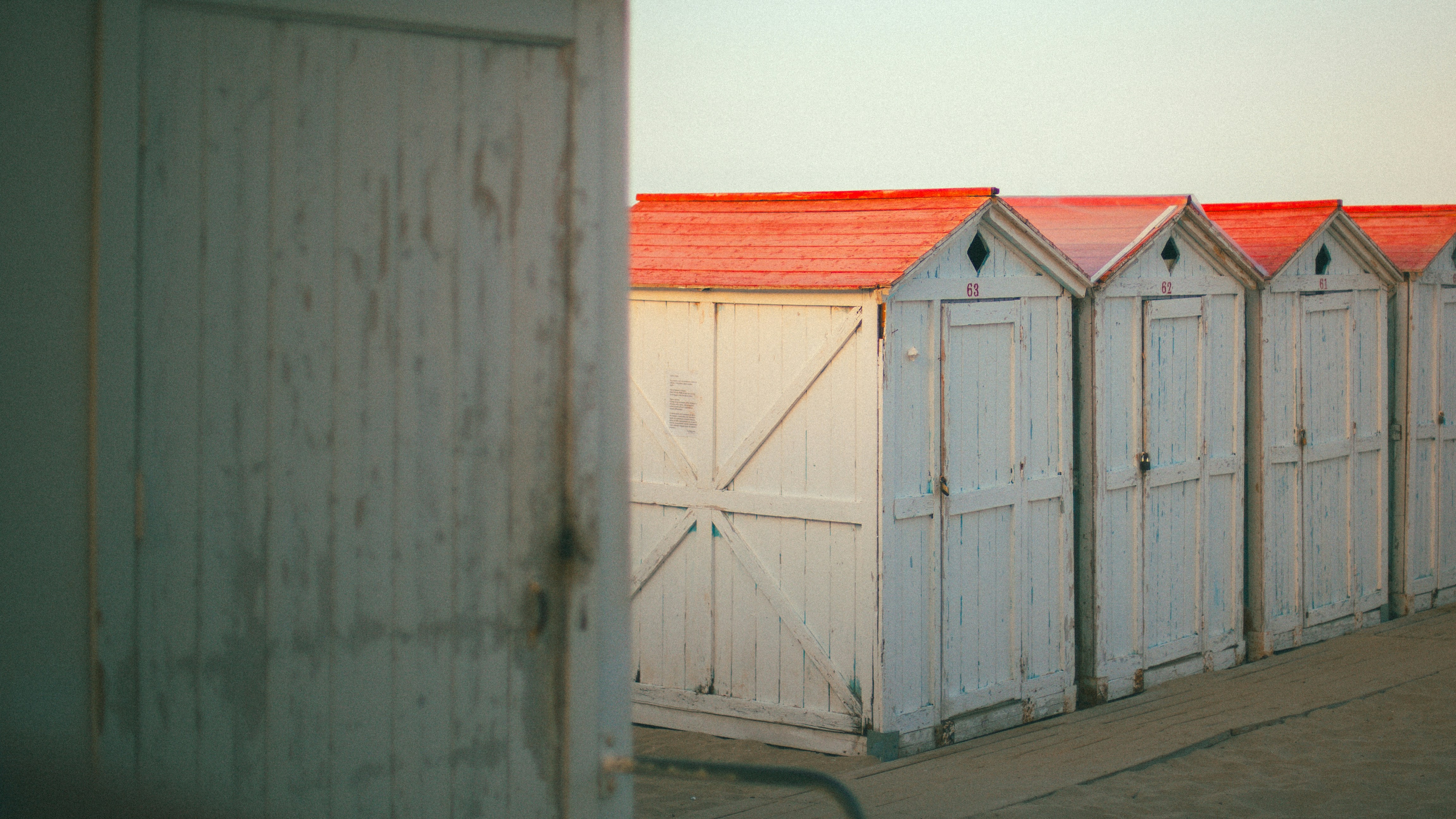 Row of weathered beach huts under a coral-roofed horizon