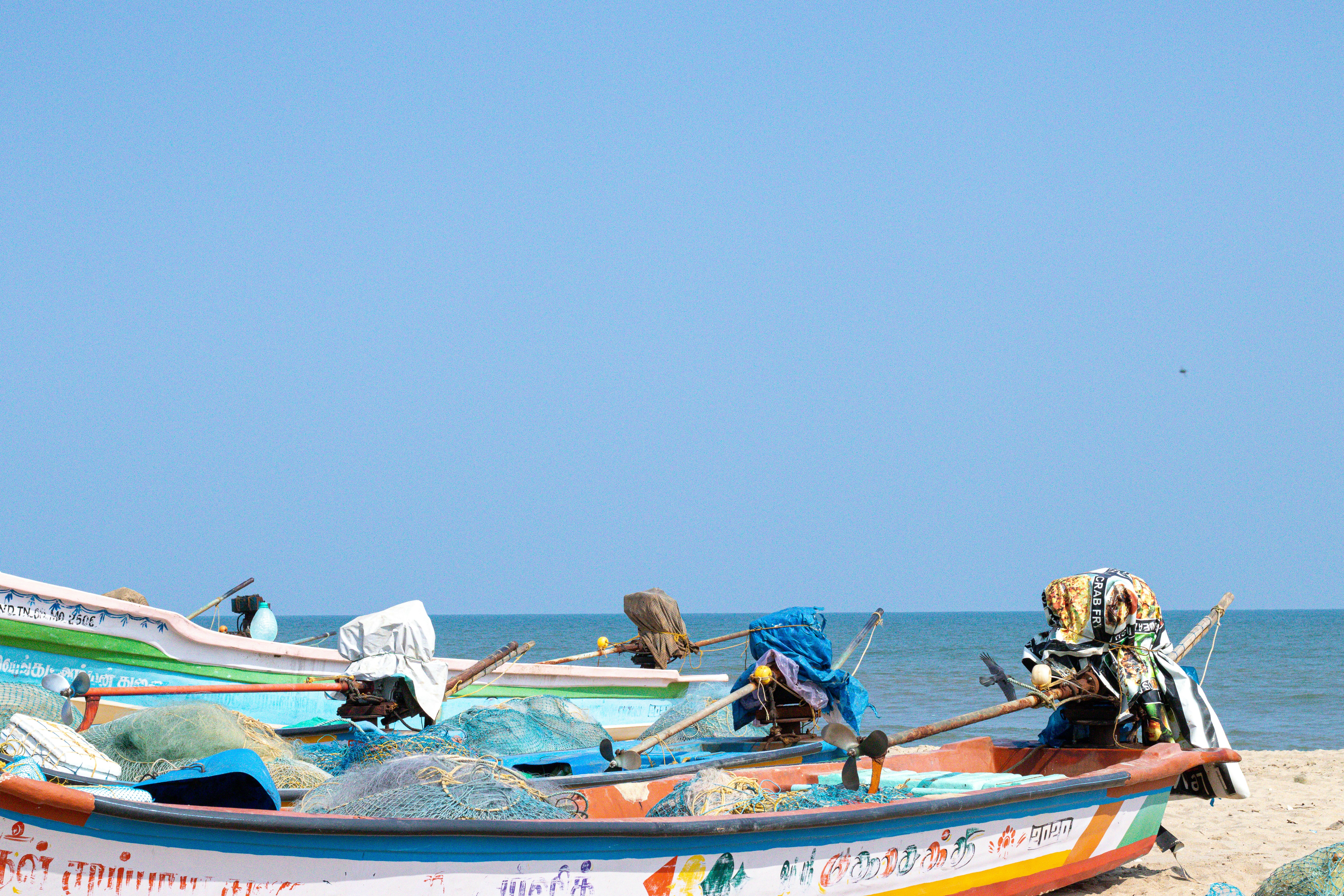Colorful Fishing Boats Rest on Sunlit Sand Beside a Calm Sea