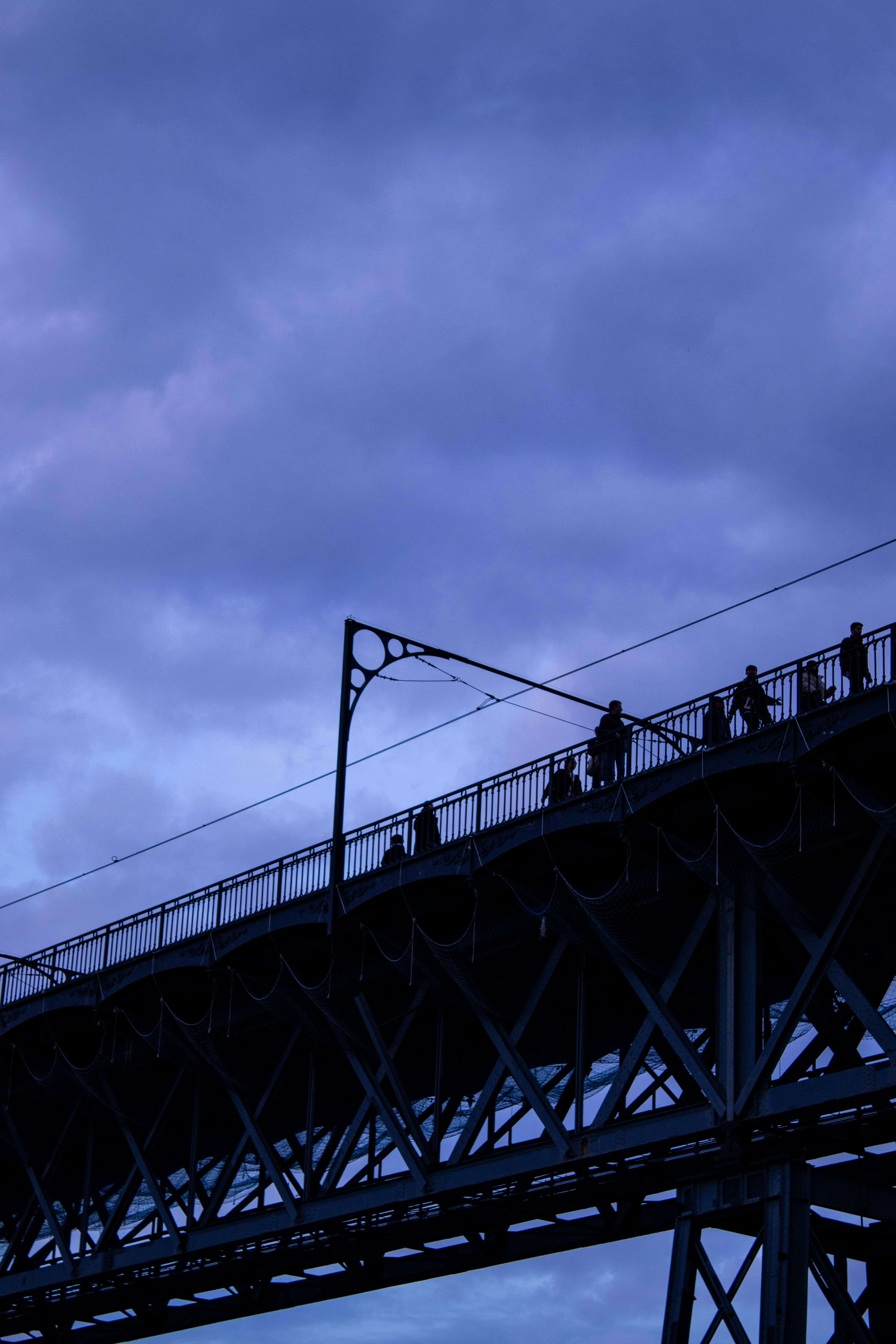 Silent silhouettes on a steel span under a cobalt dusk