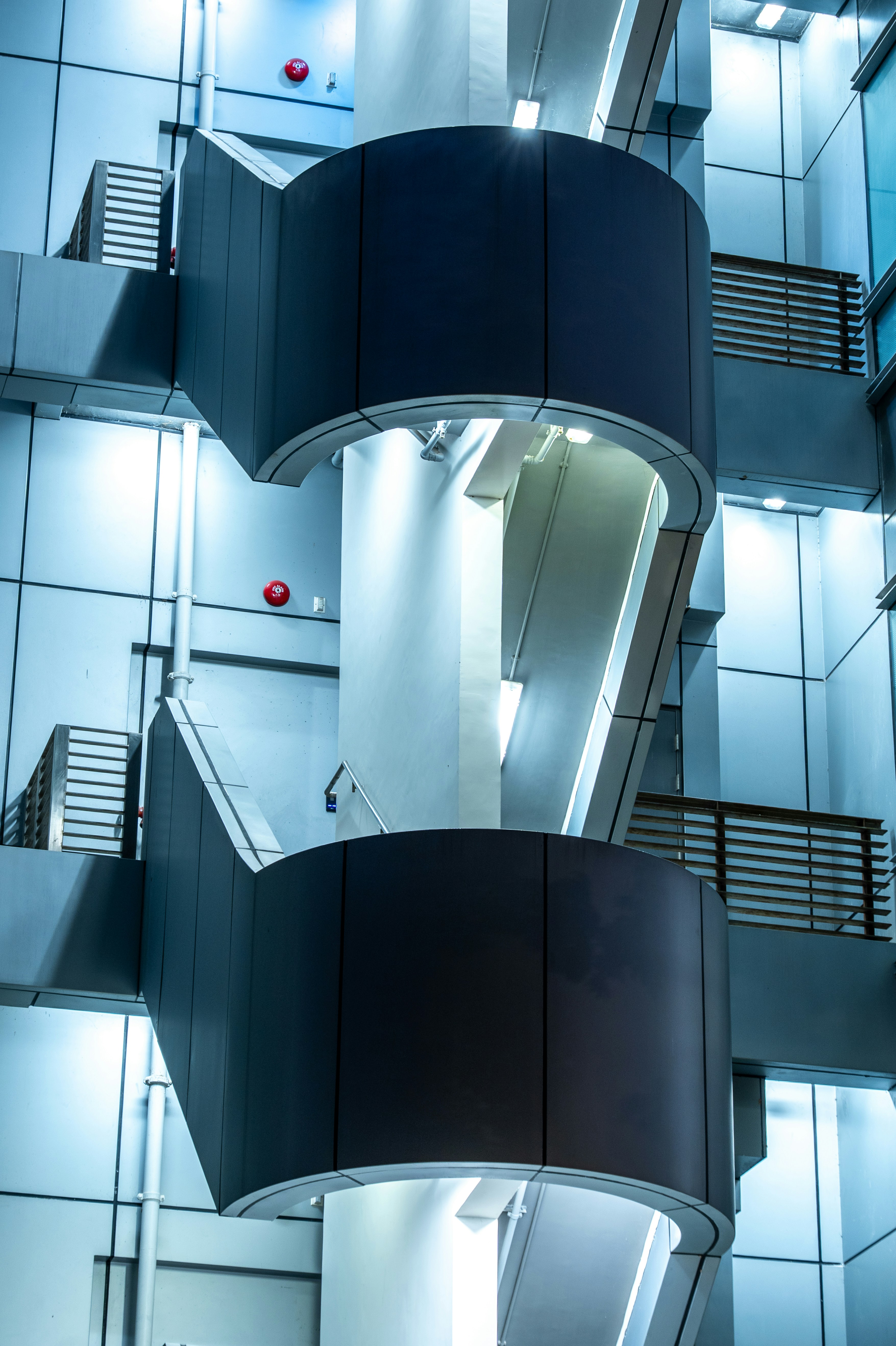 Industrial Helix: Elevators and Light in Blue-Tinted Atrium
