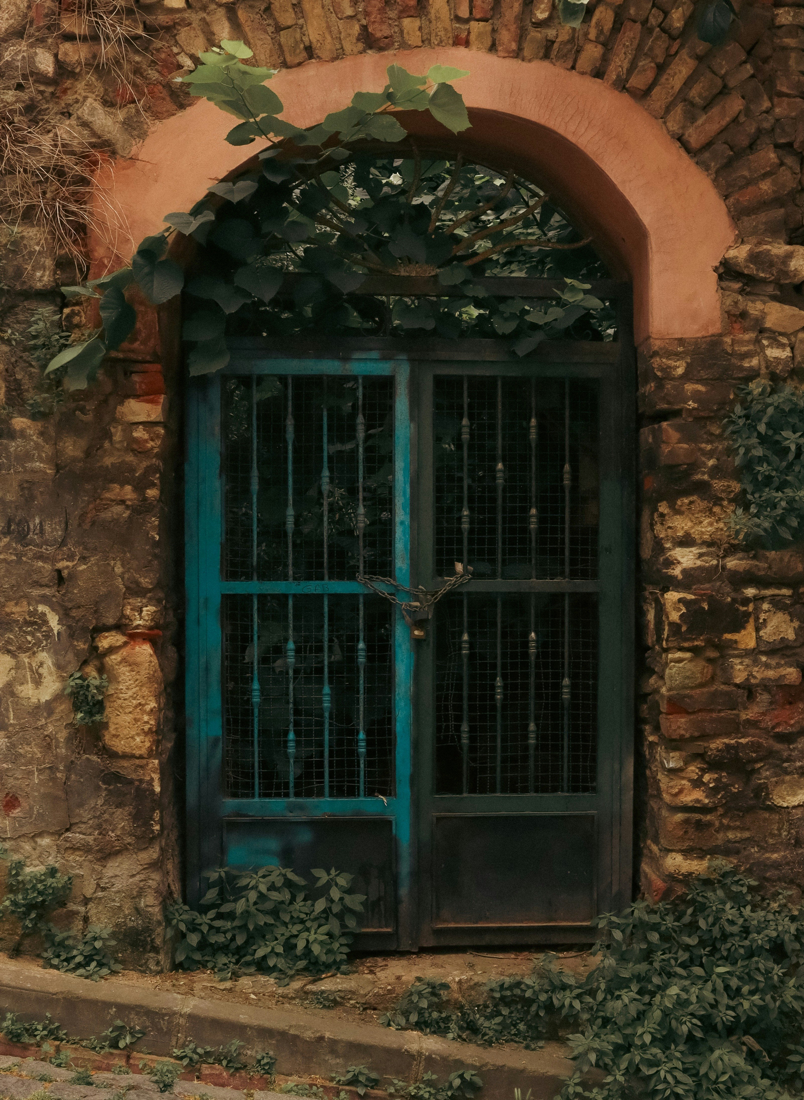 Overgrown Blue Gate Beneath a Crumbling Arch
