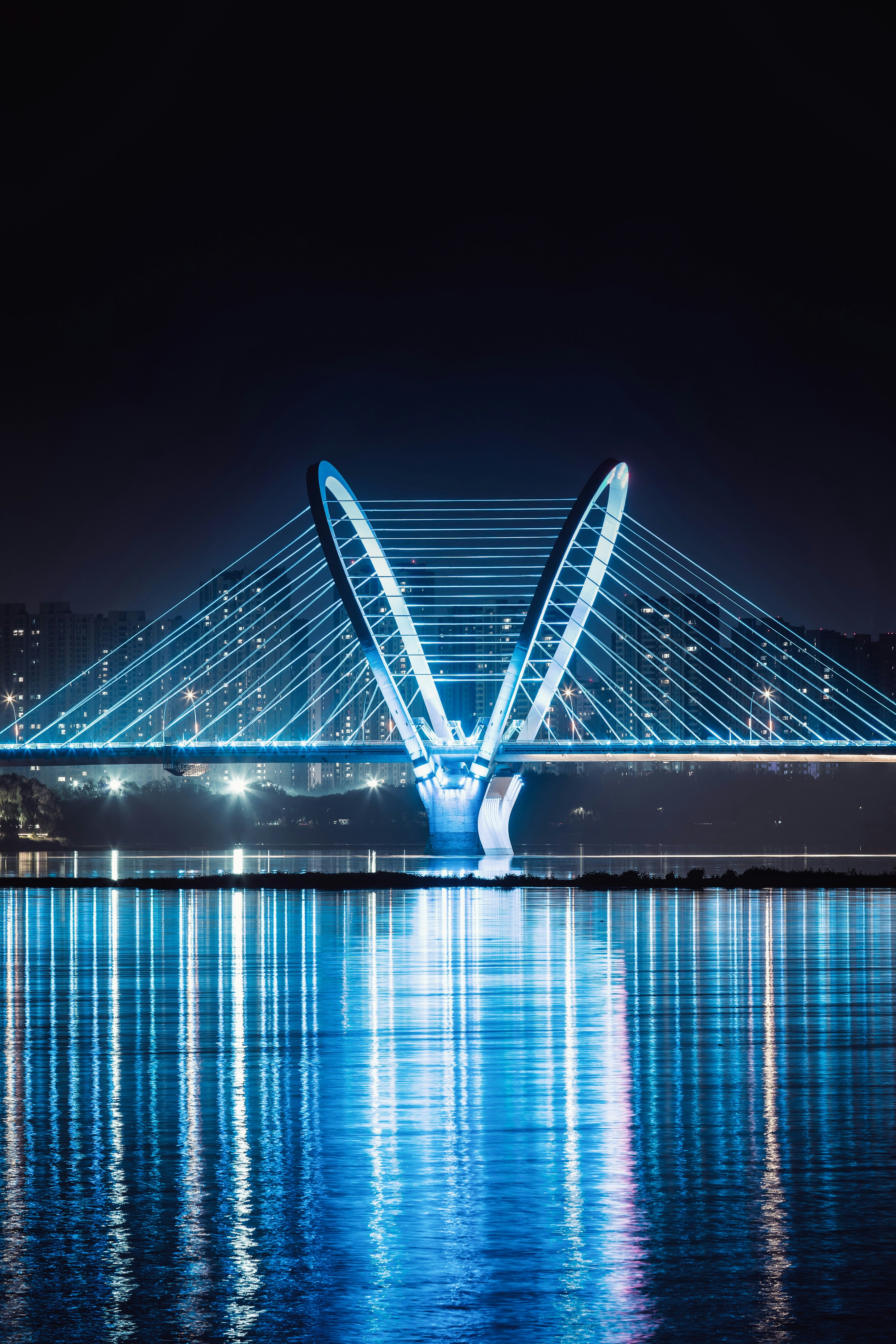 Blue Arch Ascent: Nighttime Cable-Stayed Bridge Illuminated
