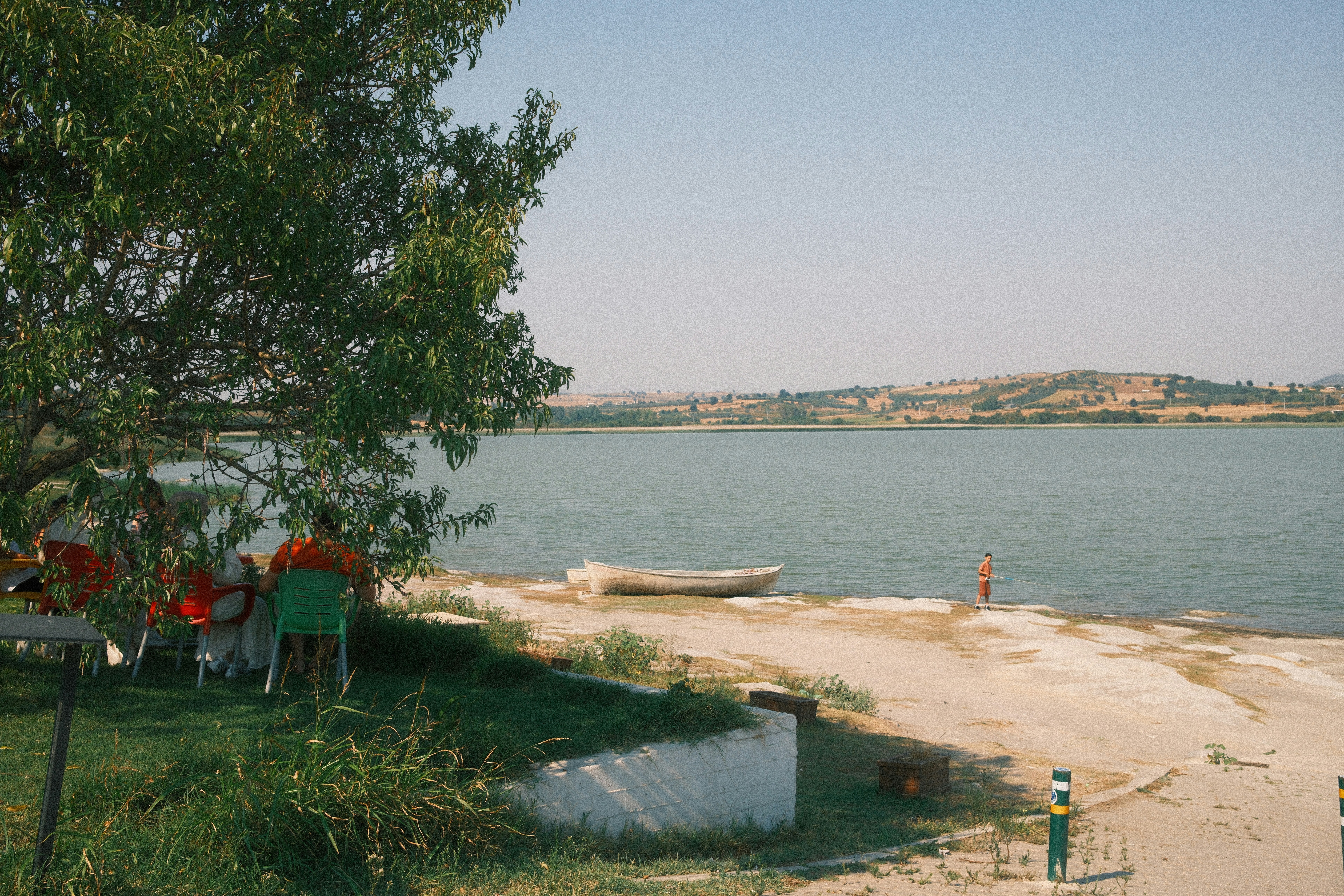 Quiet Lakeside Scene with Awned Shade and Distant Boat