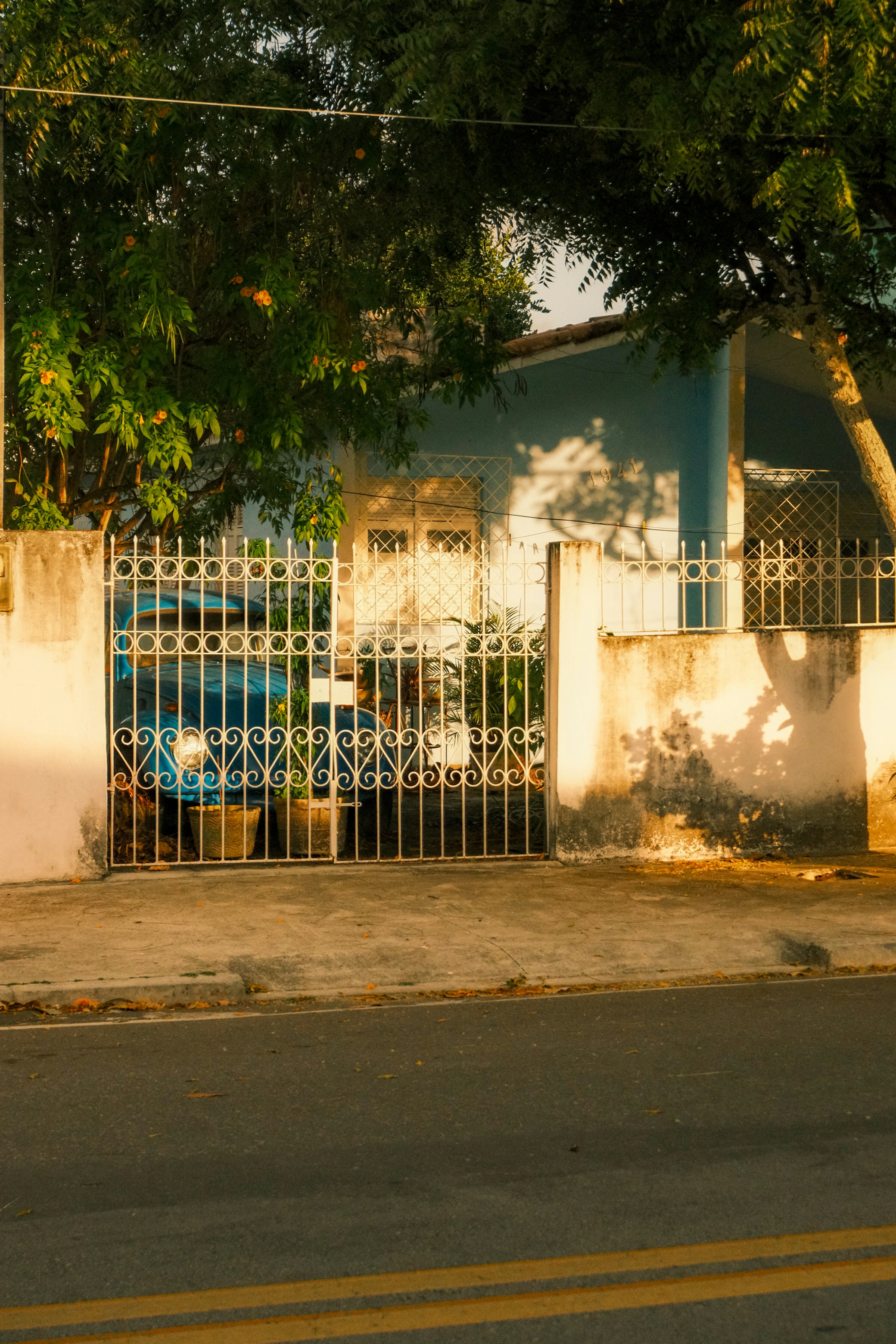 Blue Car Behind Wrought-Iron Gate in Quiet Corner