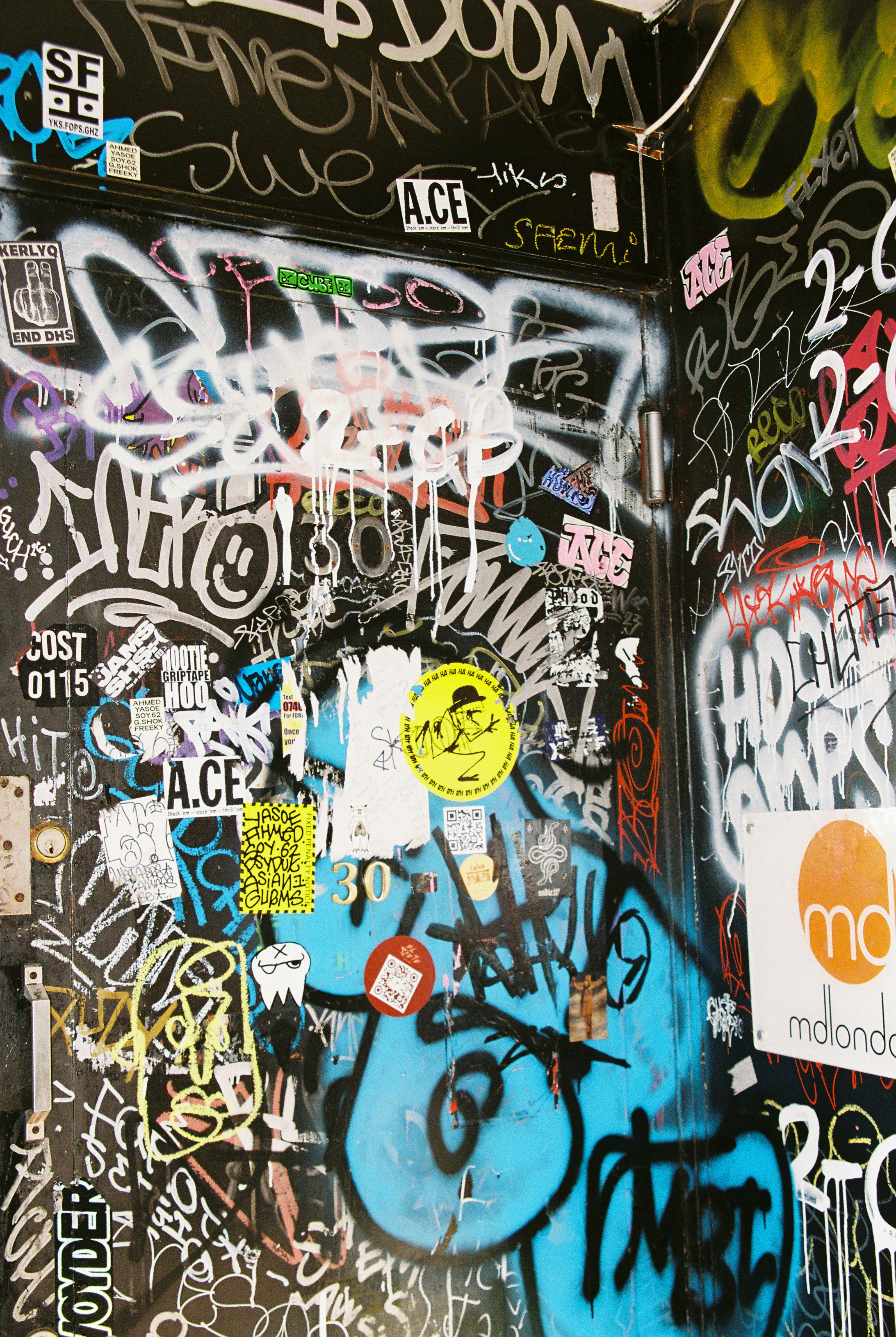 Urban Graffiti Mosaic: A Doorway of Tags and Color
