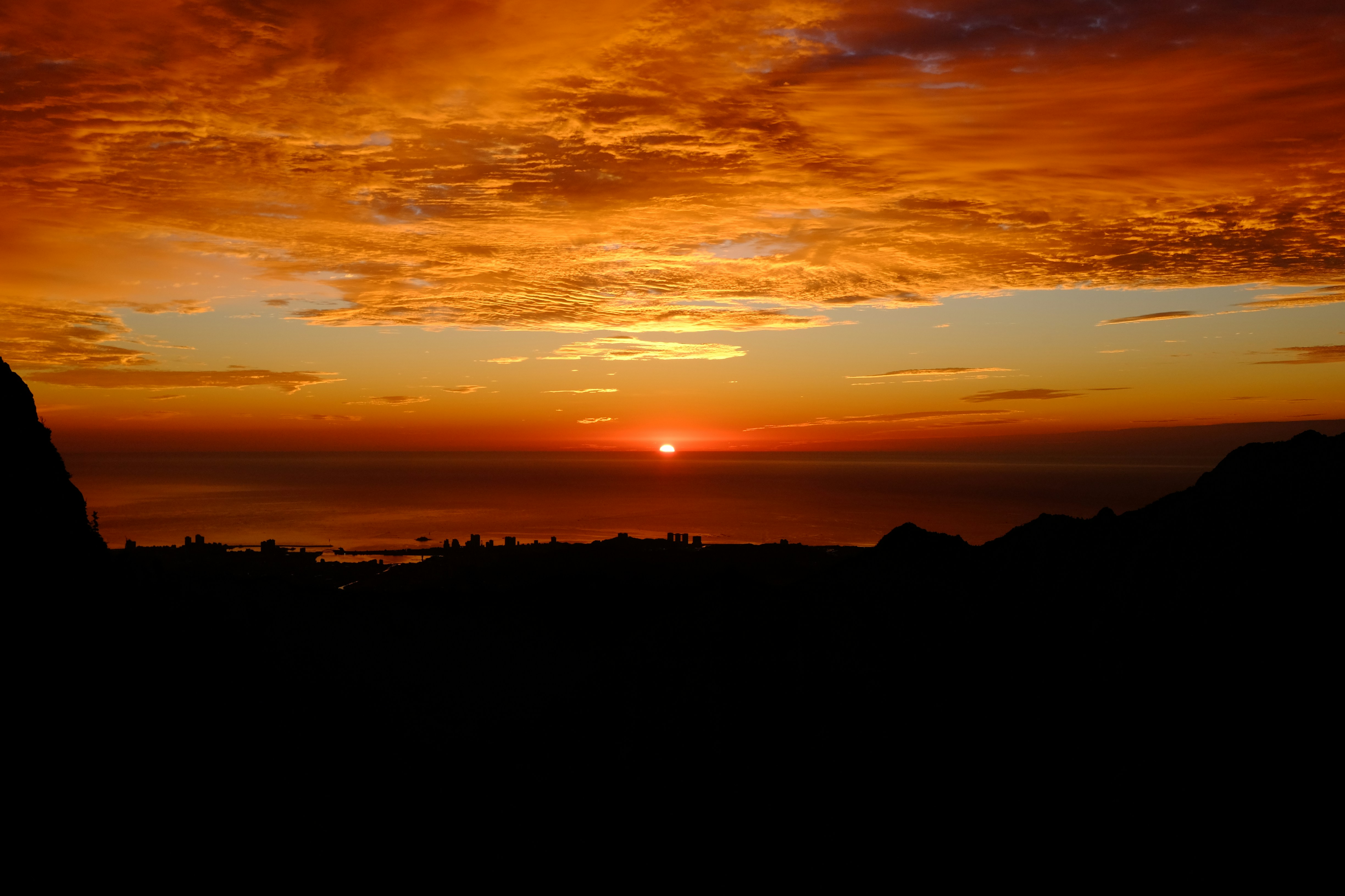 Sunrise at the Quiet Rim: Fiery Sky Over a Mountain Horizon