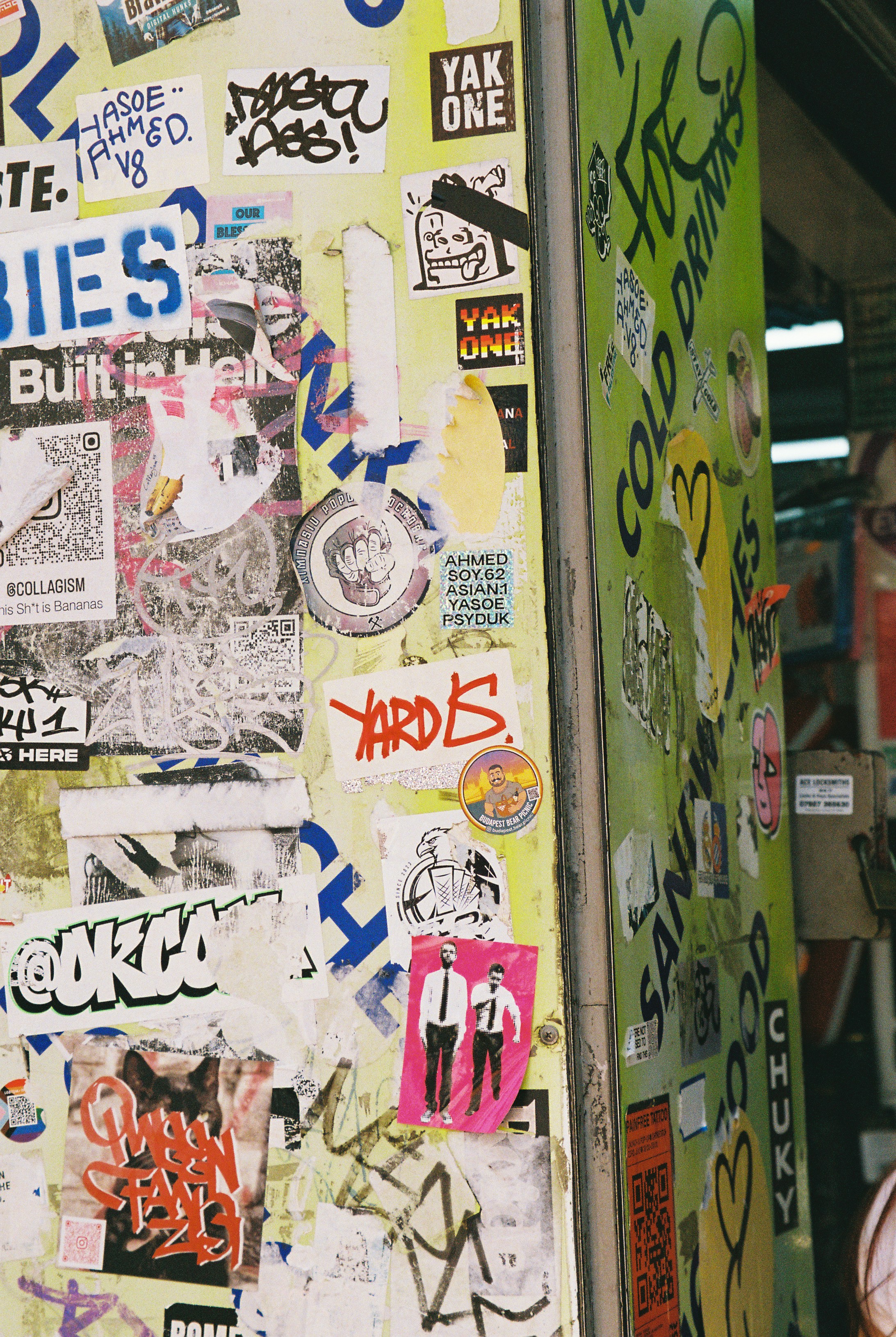 Stickered Wall of Urban Pop: Colorful Layers of Street Art Collage