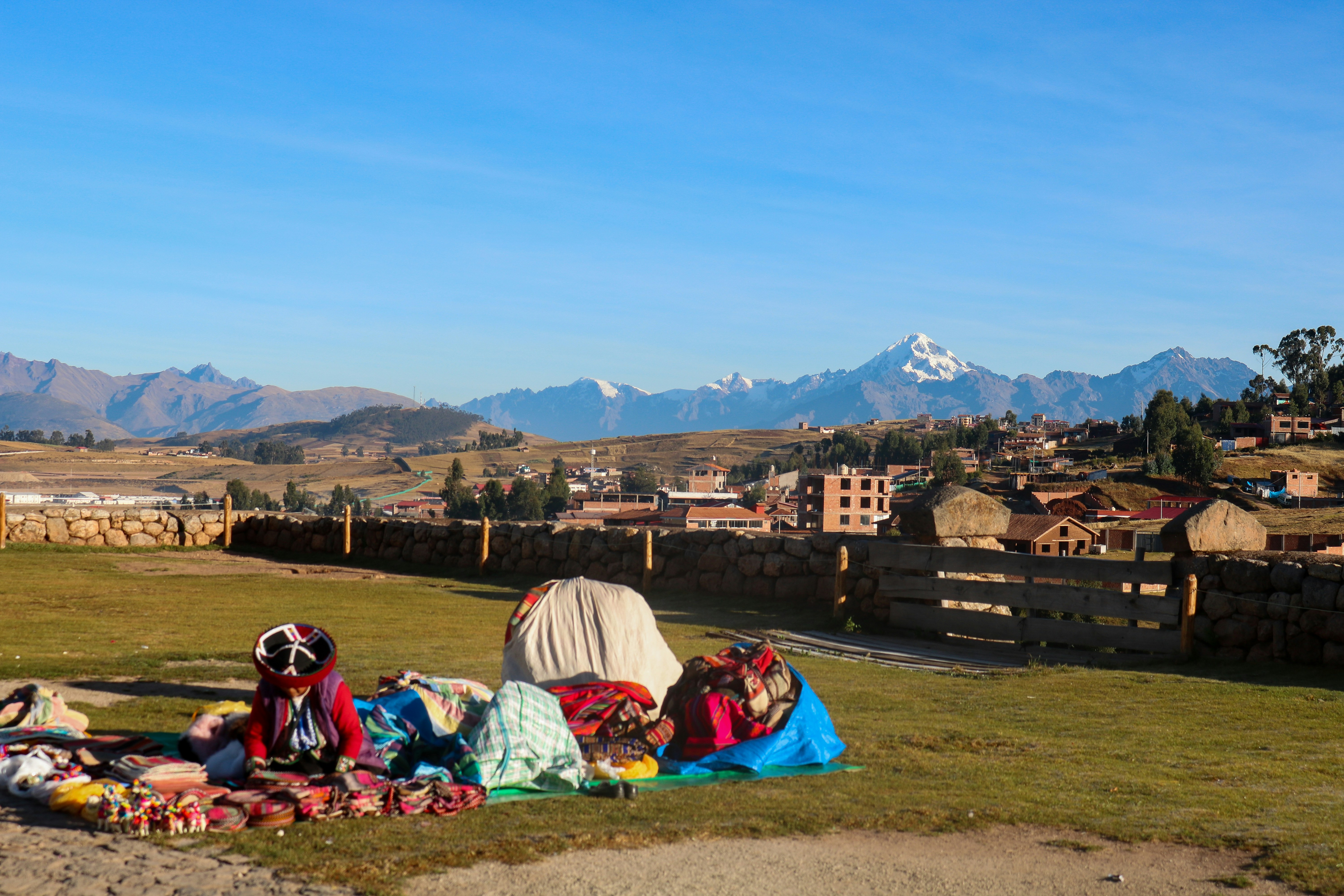 Colorful textiles on the grass with distant Andean village and snow-capped peaks