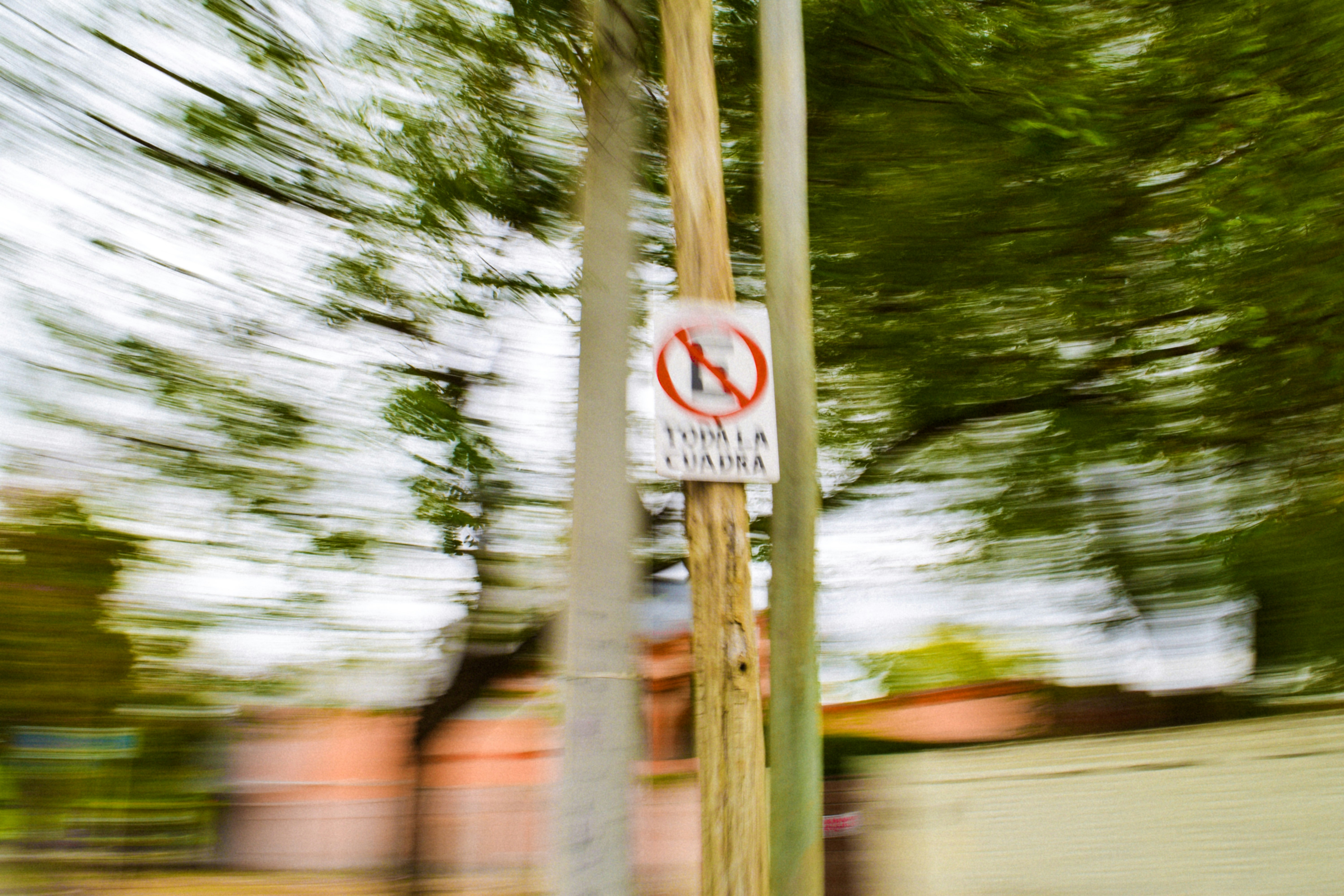 Blurred street scene with a central pole and a no-entry sign, conveying motion and urban stillness in a cyclist-like spin.