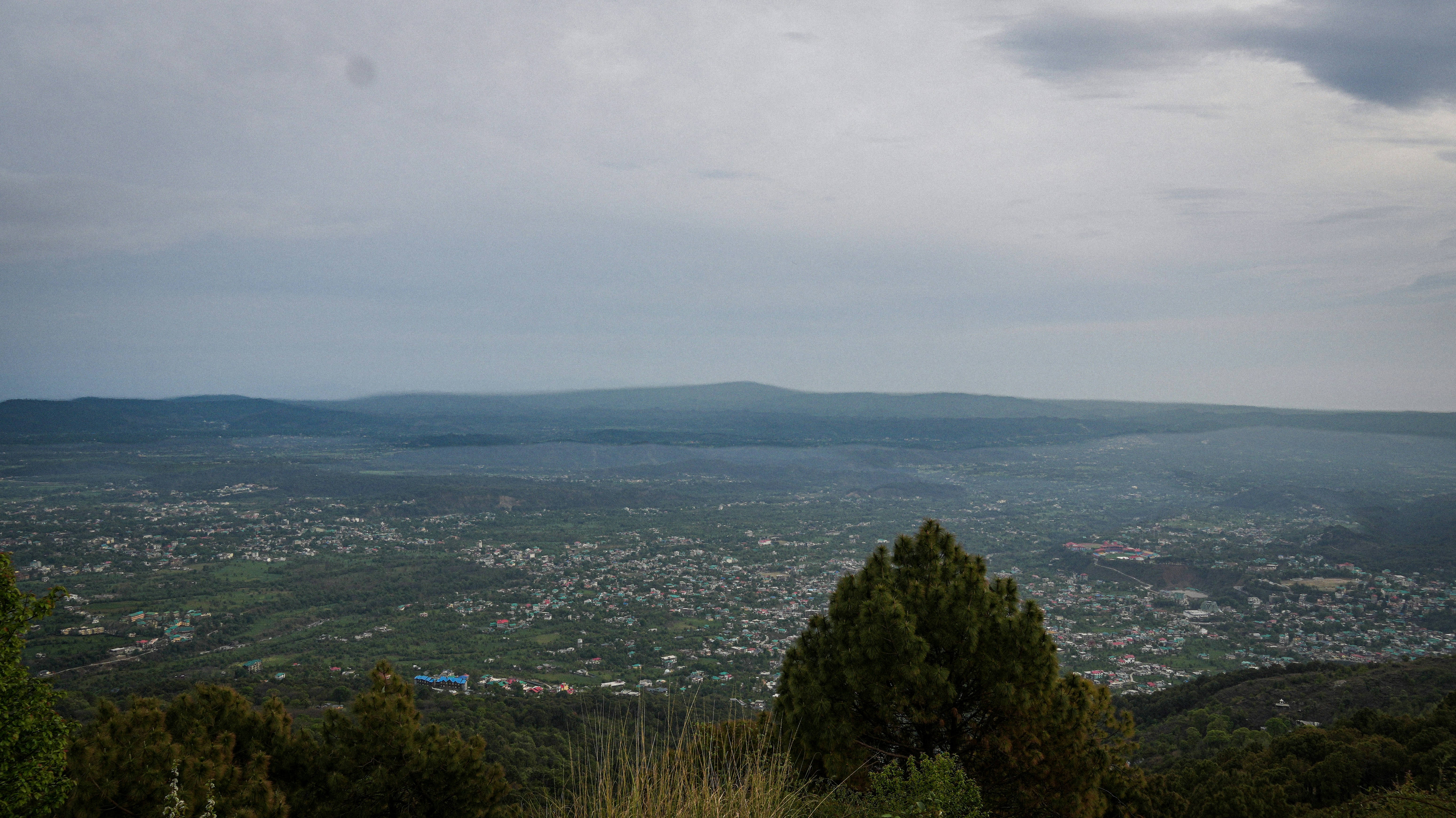 Distant valley and townscape spread across rolling hills under a broad, cloudy sky.