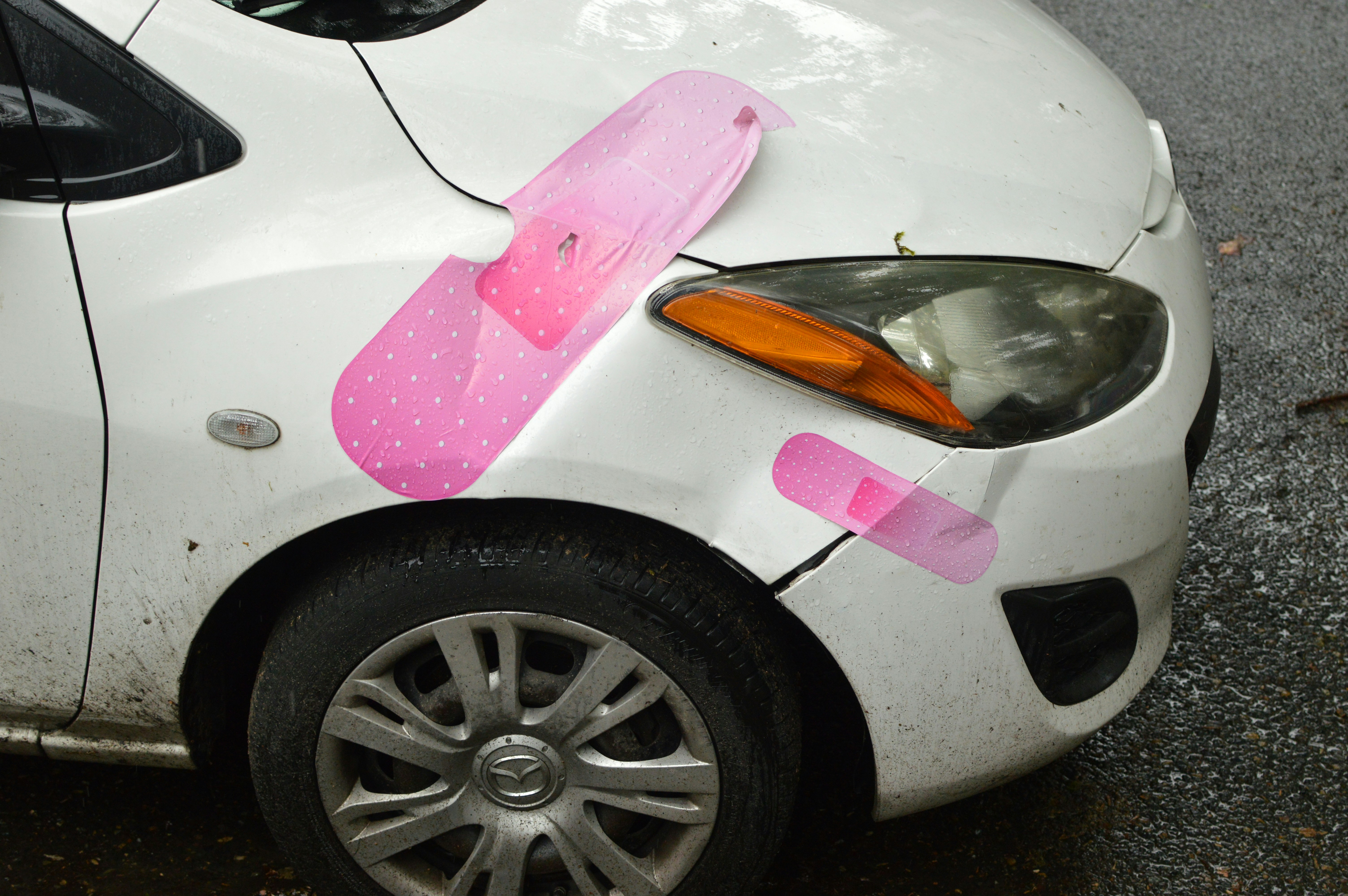 Pink Band-Aid Graffiti on a Scratched Car Hood