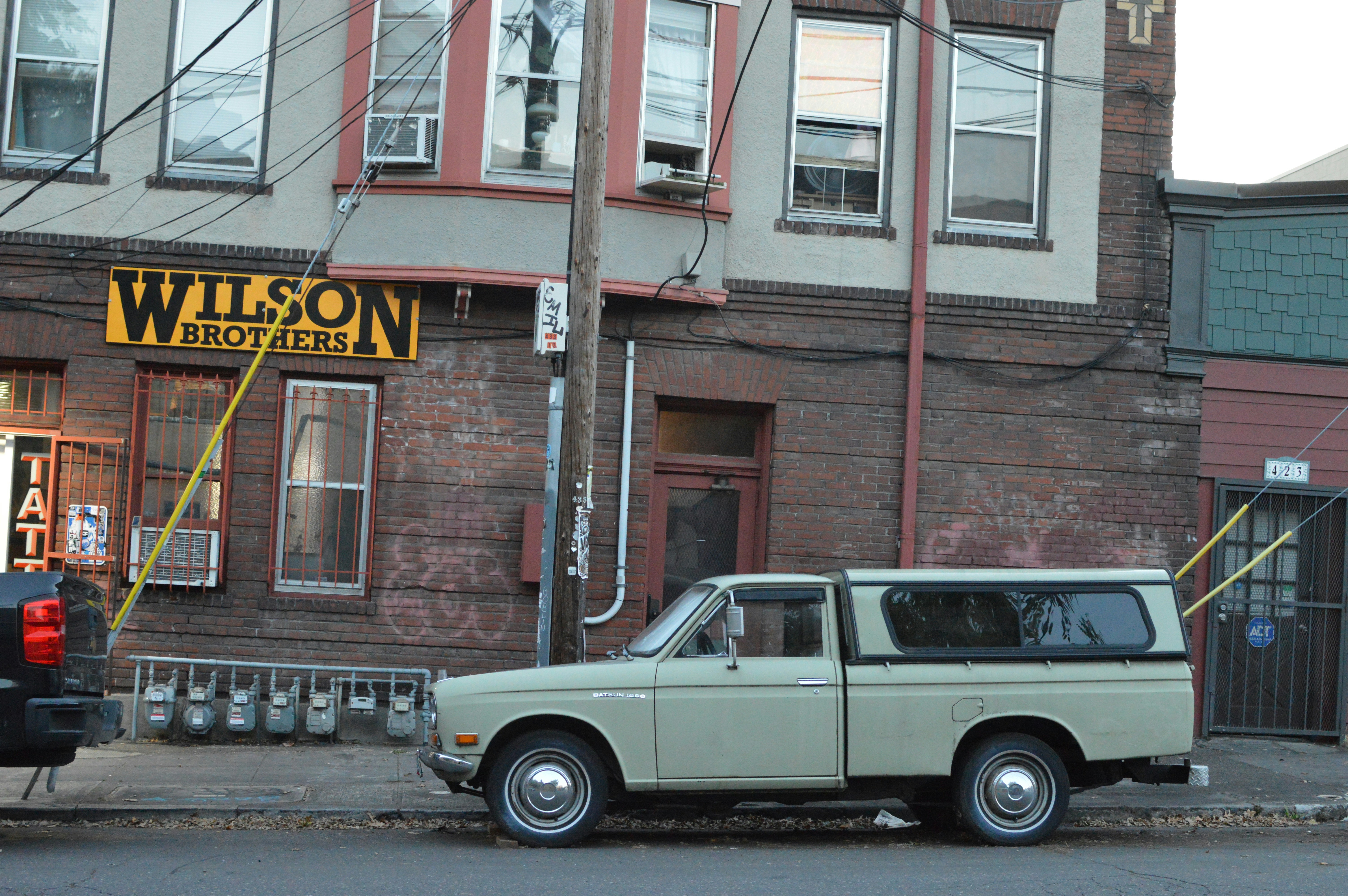 Cream van under a weathered brick storefront