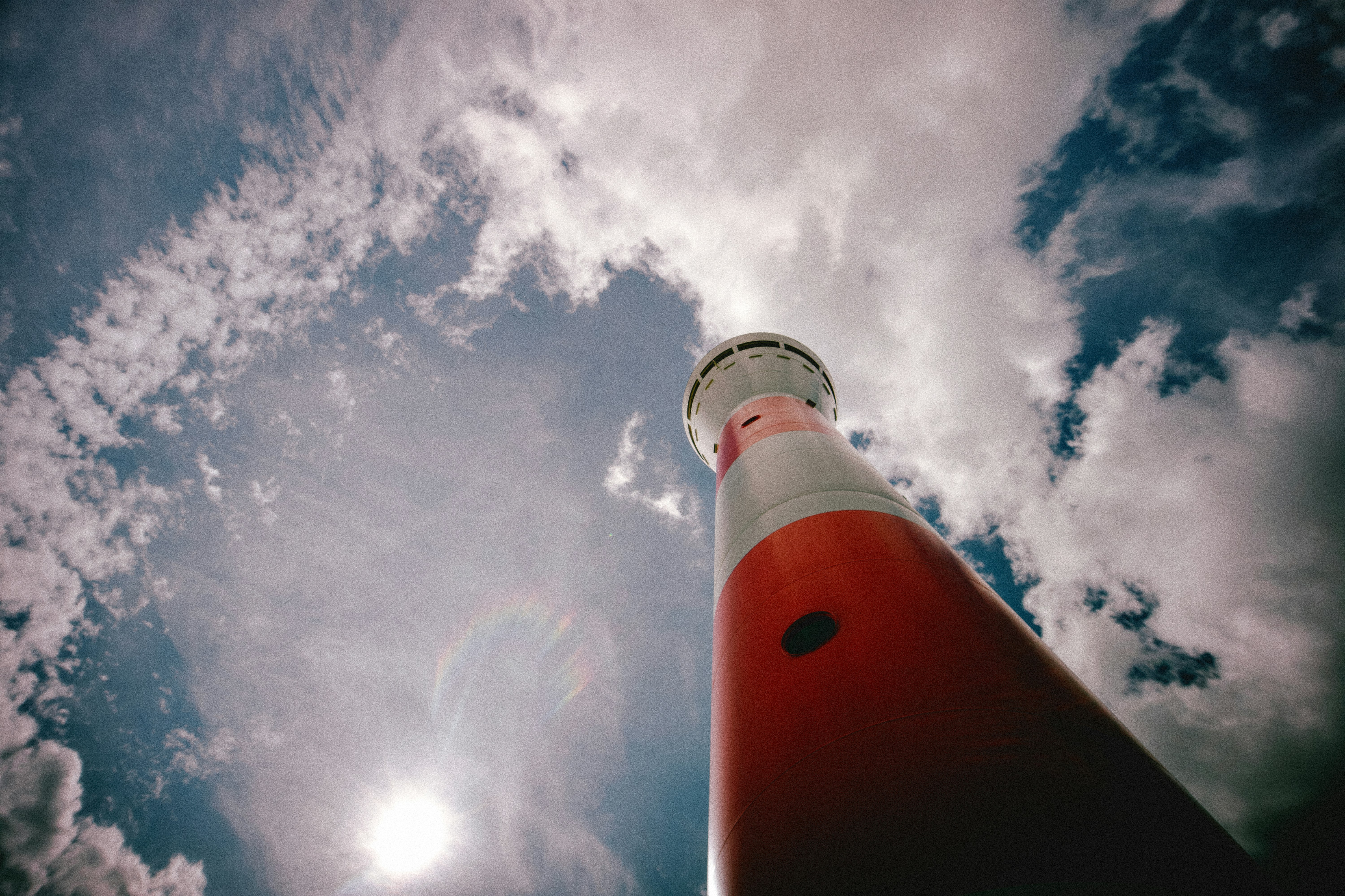 Skyward Beacon: A Low-Angle Portrait of a Red Lighthouse