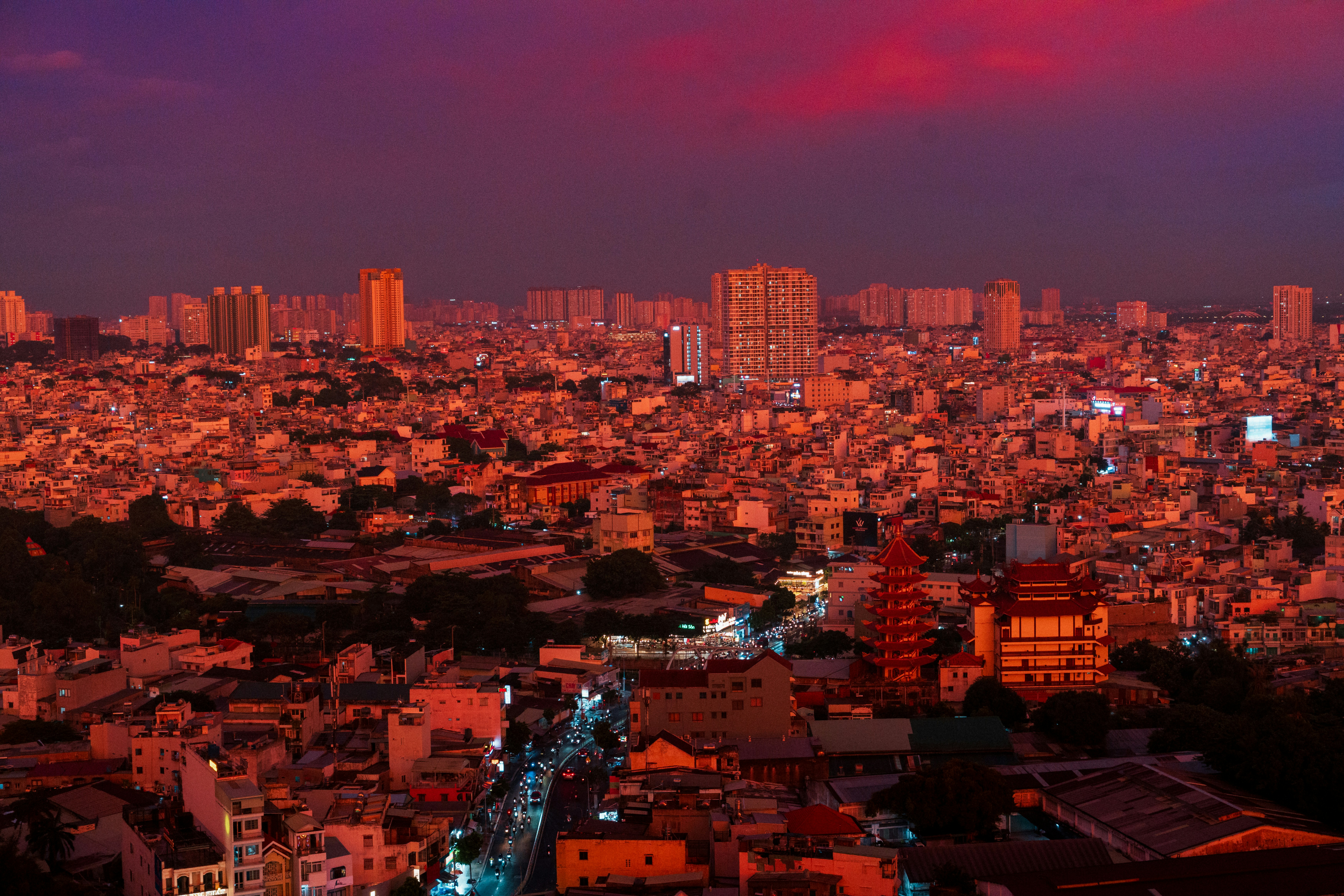 Dense cityscape bathed in warm dusk light with clustered buildings and a hint of street activity; urban tapestry emphasizing depth and horizon.