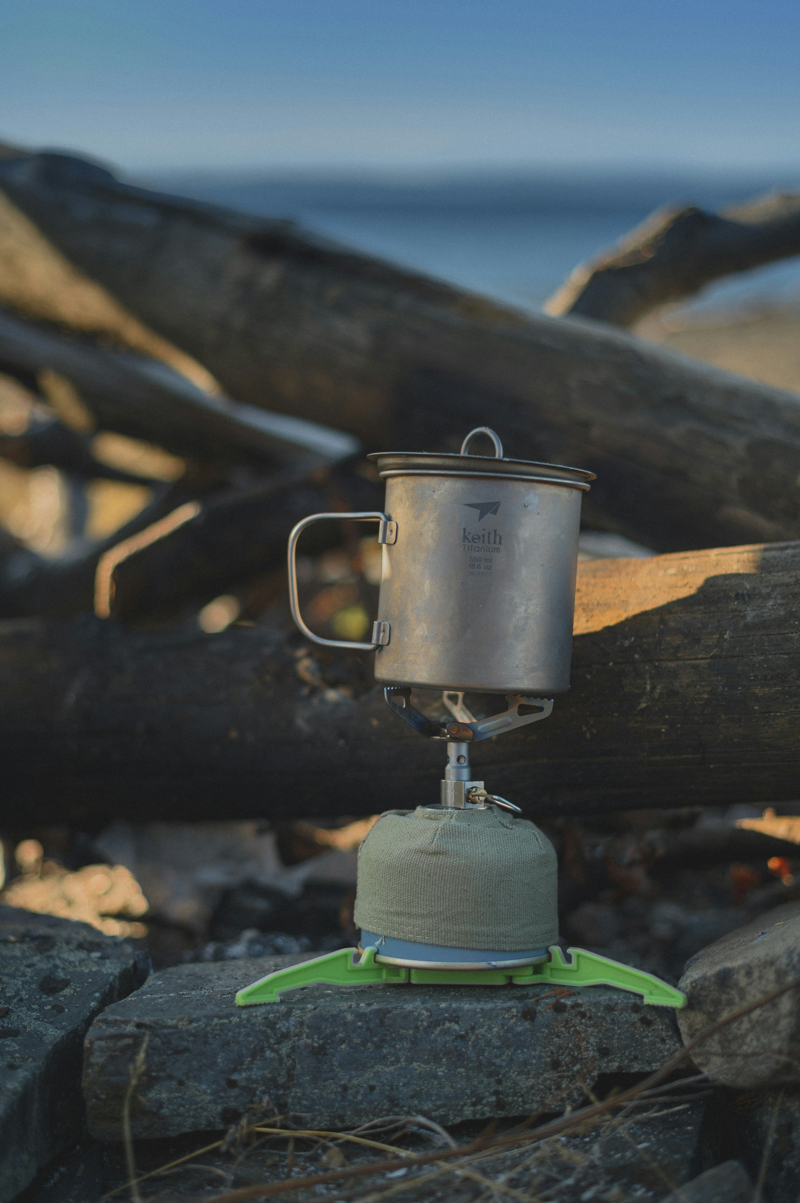 A Compact Stove on Driftwood at the Shoreline