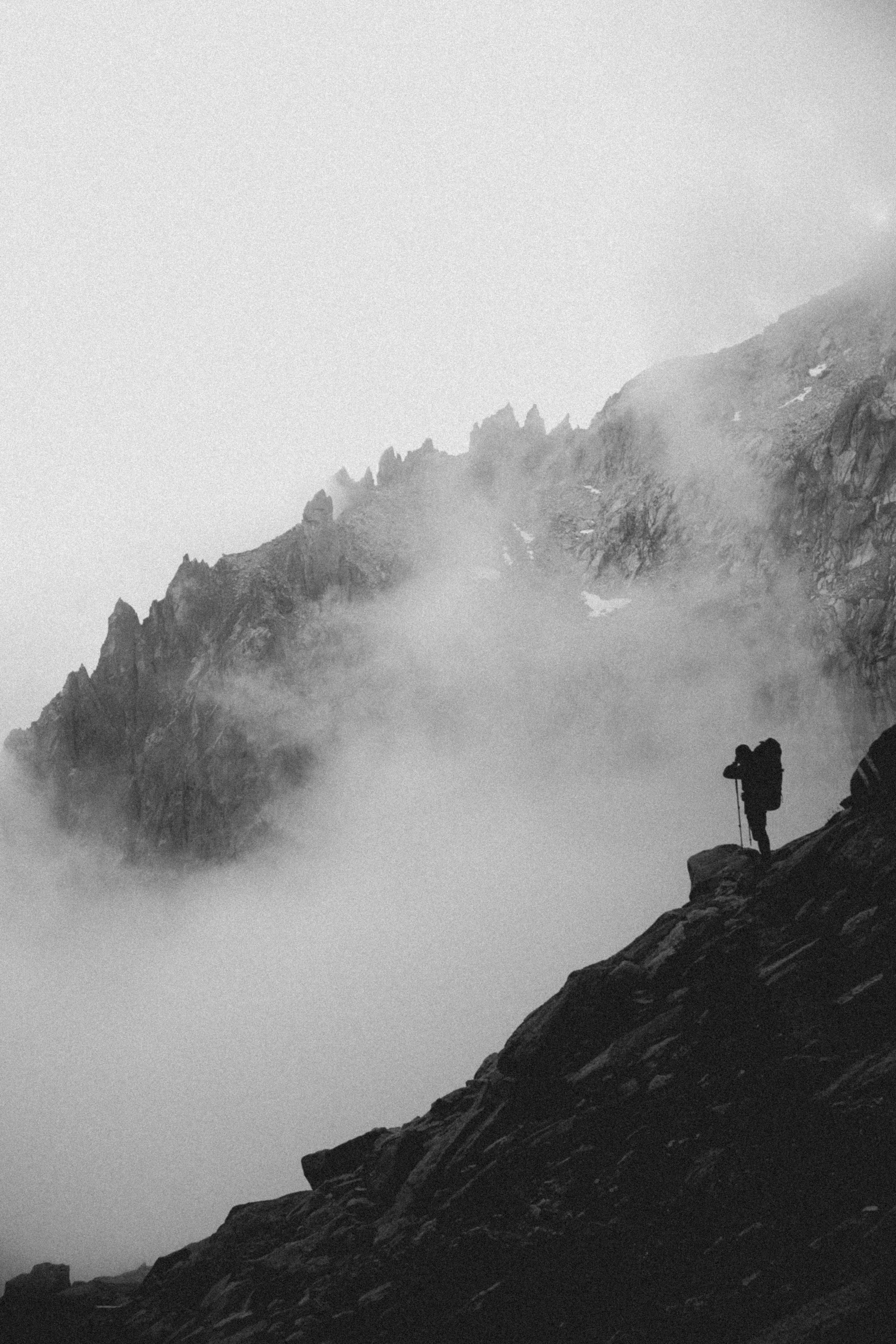 Silhouette on the Ridge: A Lone Photographer Against Mist and Jagged Peaks