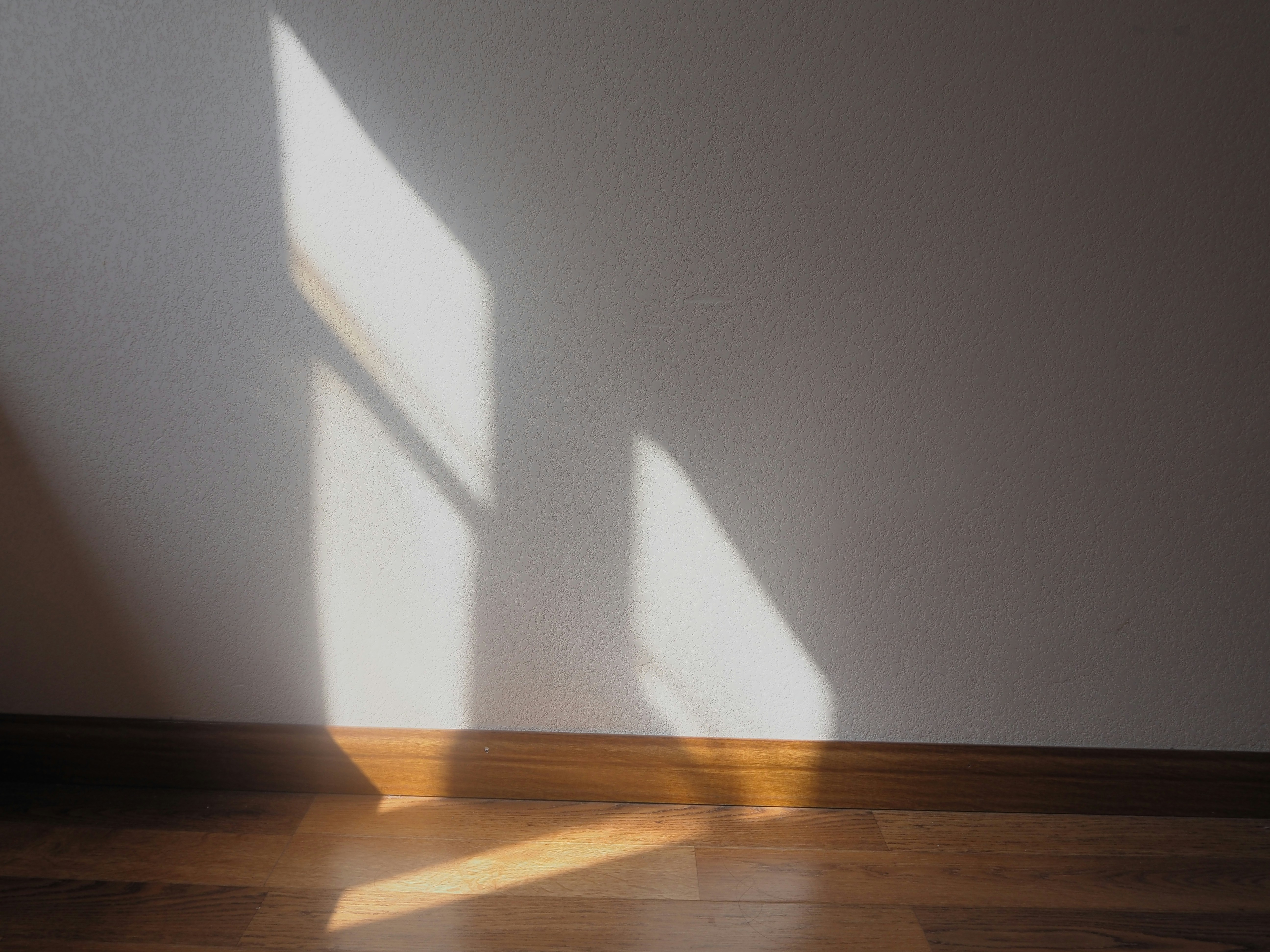 Sunlit Geometry: Shadowed Floor and Baseboard in Quiet Interior