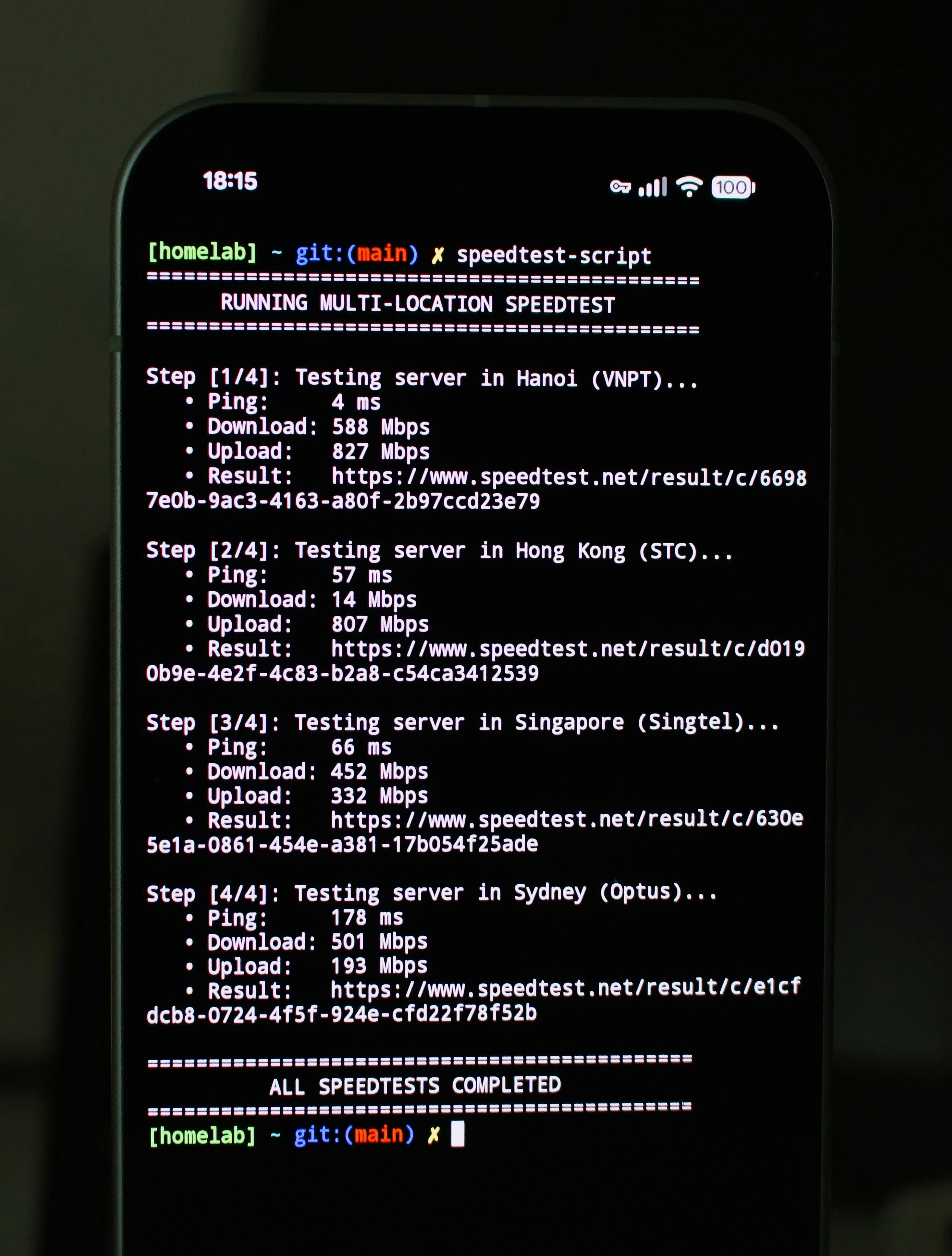A close-up of a smartphone displaying multi-location speedtest results in a dark setting. The screen shows lines of text with server locations and speeds; the image depicts a clear emphasis on data readout and debugging activity.