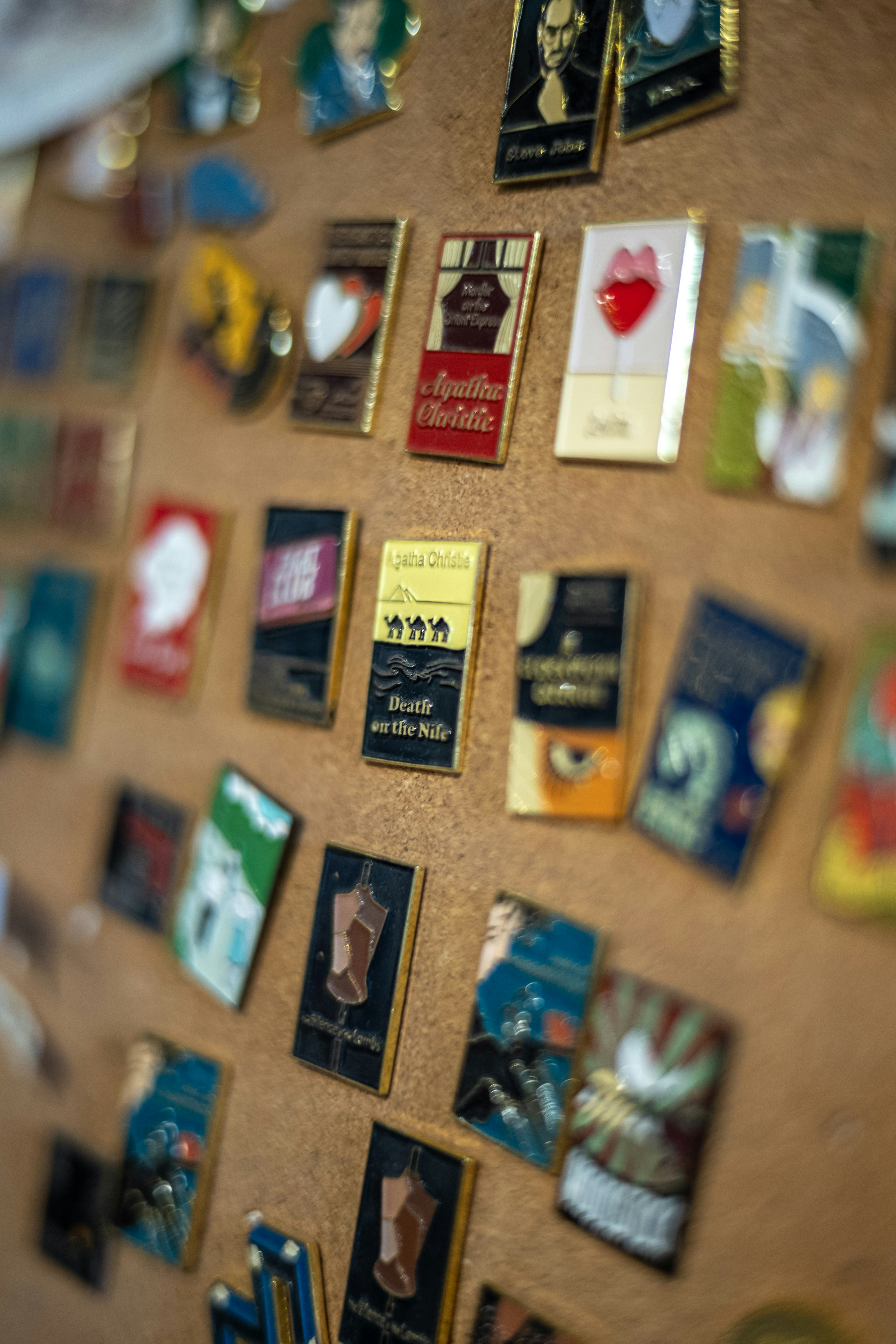 Pinned Miniatures: A Wall of Colorful Cocoa Booklets on a Corkboard